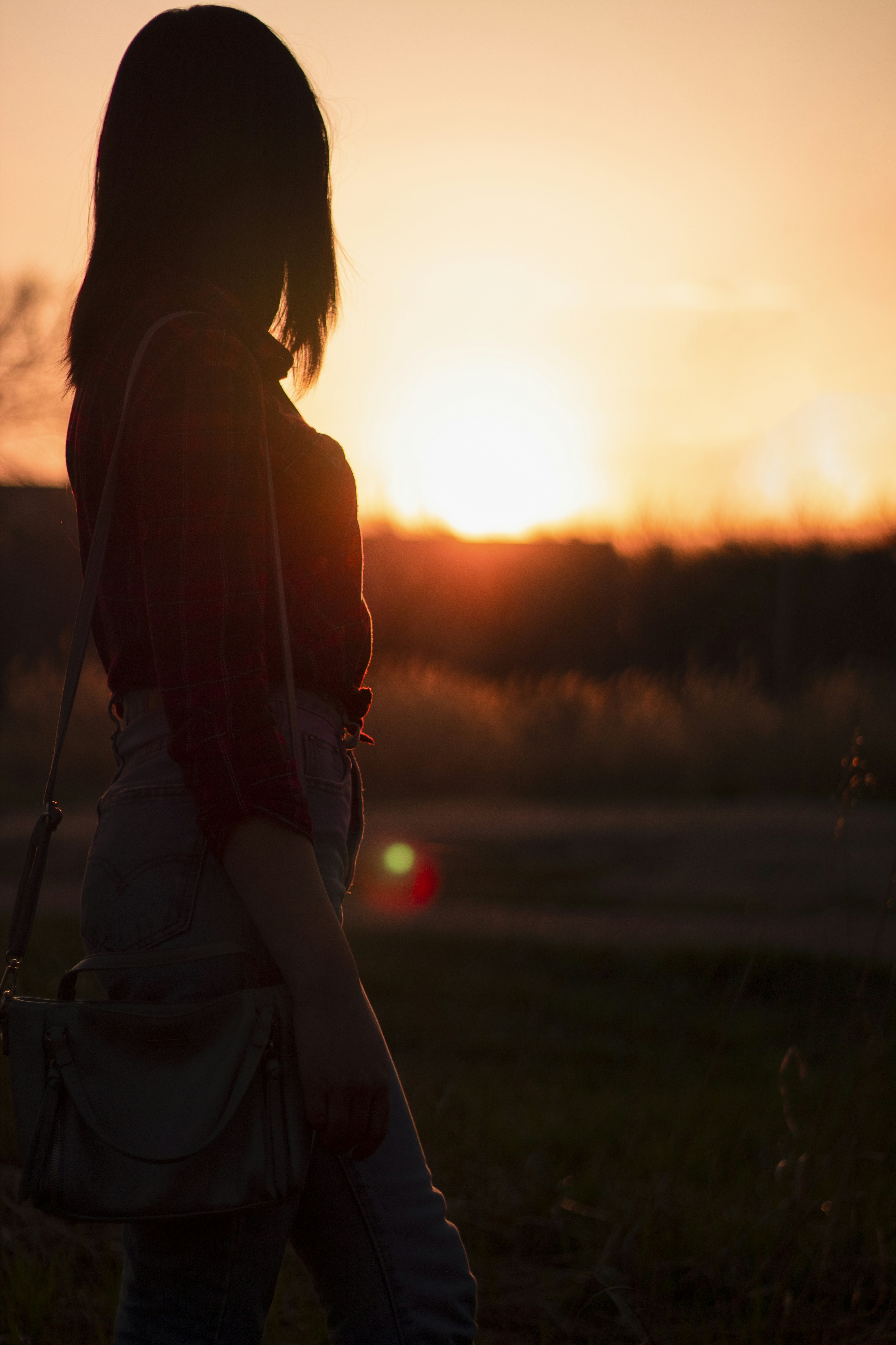 A silhouette of a person stands against a glowing sunset, capturing a moment of tranquility in nature.
