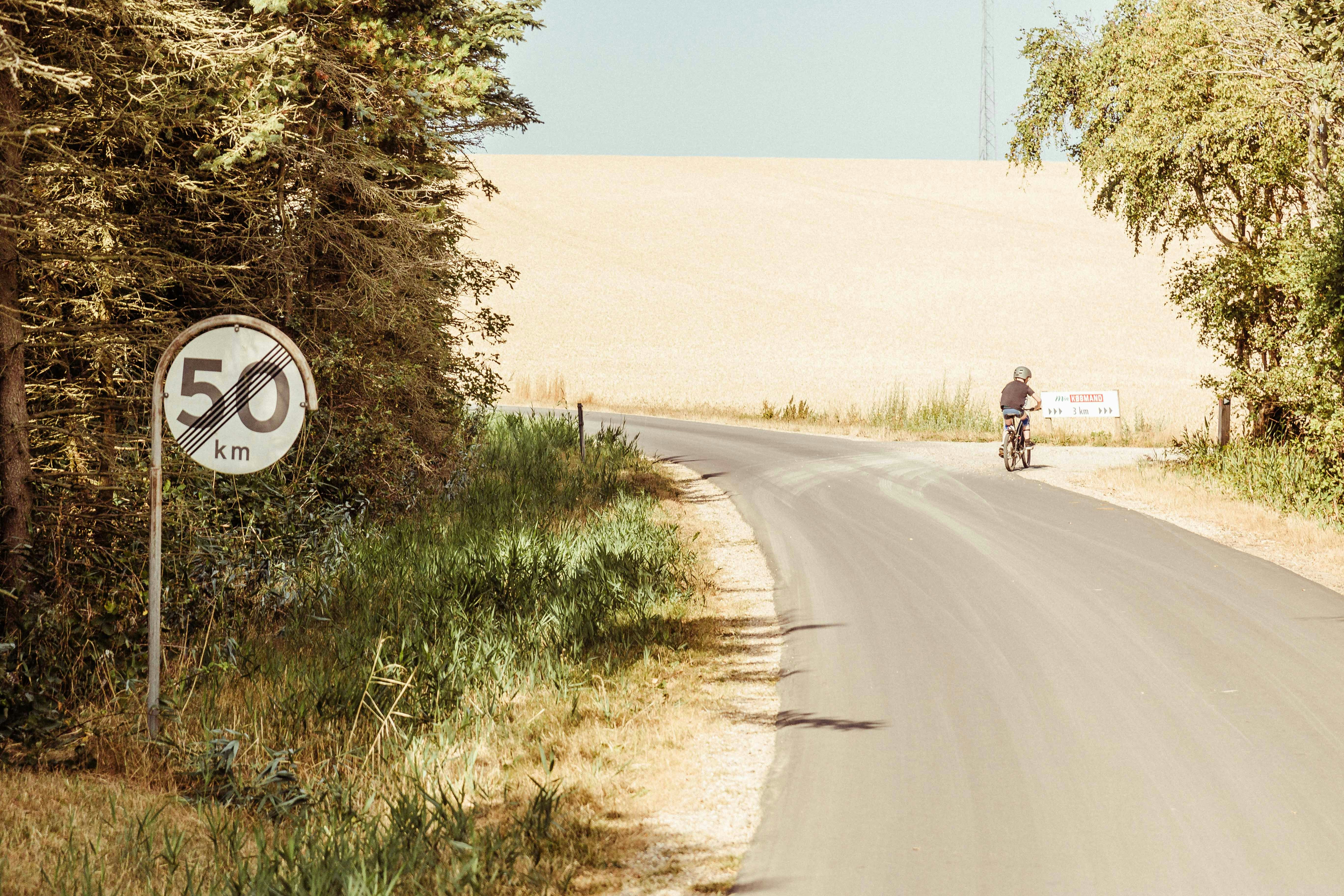 Dusty Dawn on the Curve: A lone cyclist on a sunlit rural road