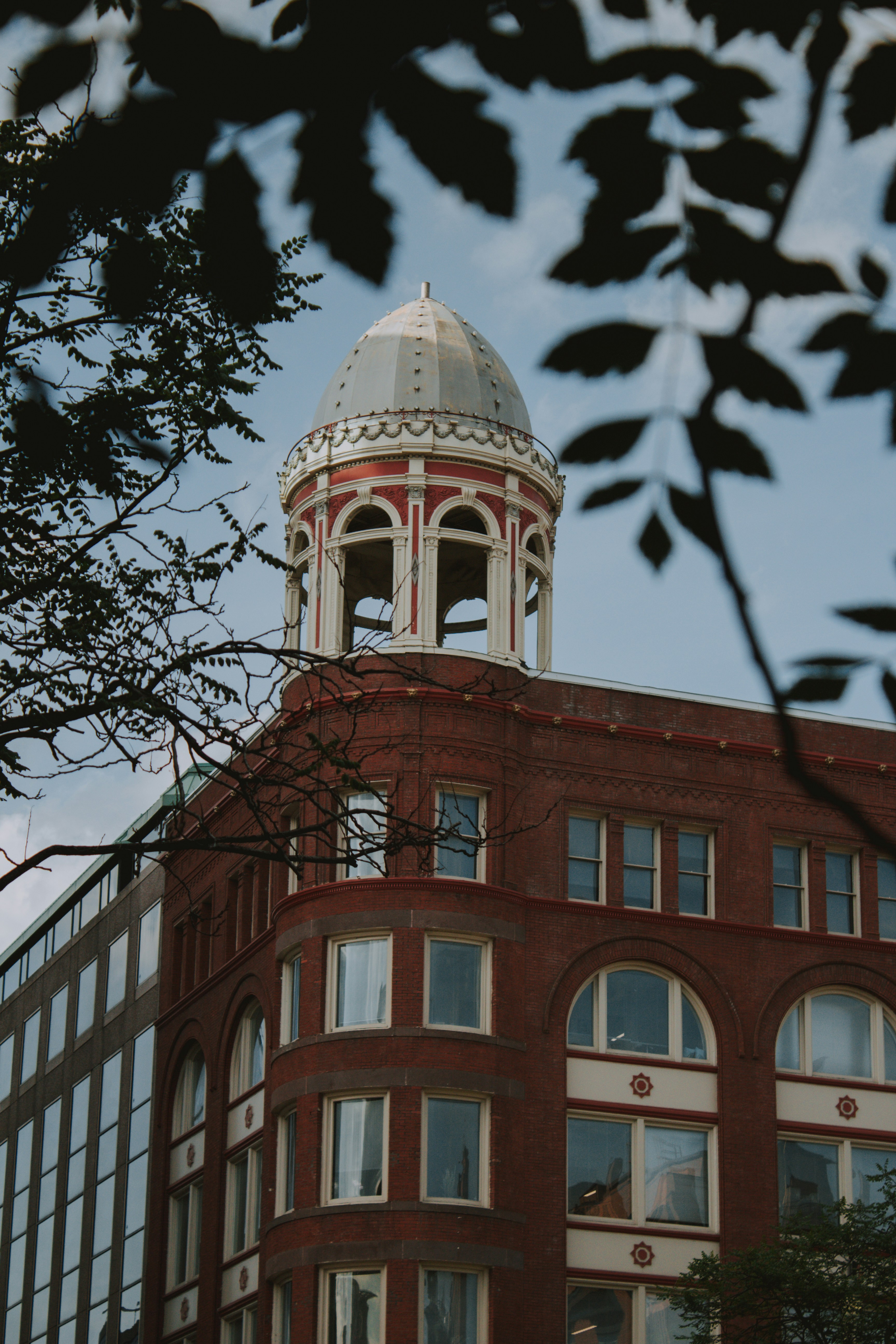 Dome Crown Above Brick Facade: A City Block Framed by Foliage