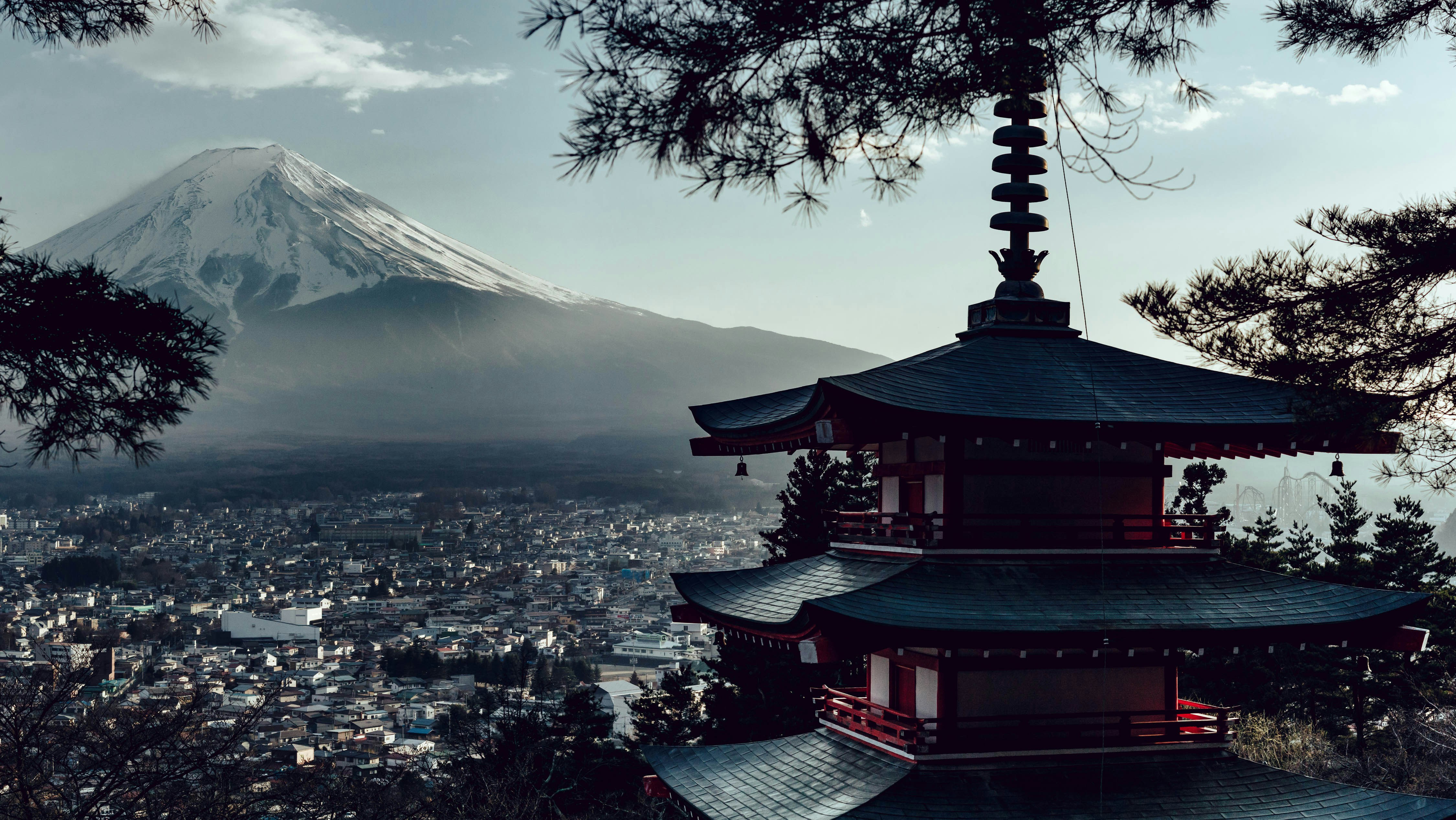Pagoda overlooking a city with Mount Fuji in the background under a clear sky.