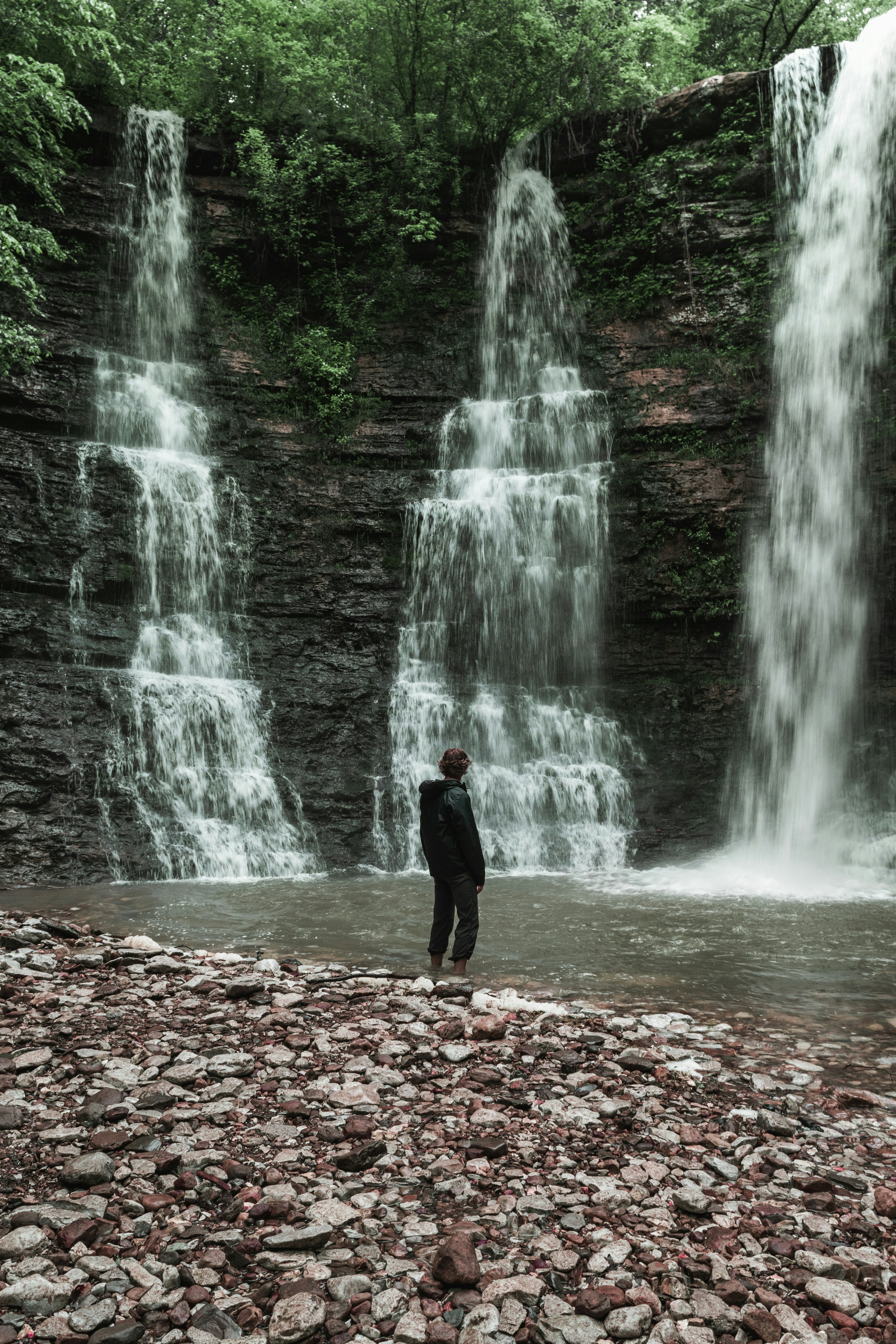 Traveler at the Edge: A Lone Figure Against a Tiered Waterfall