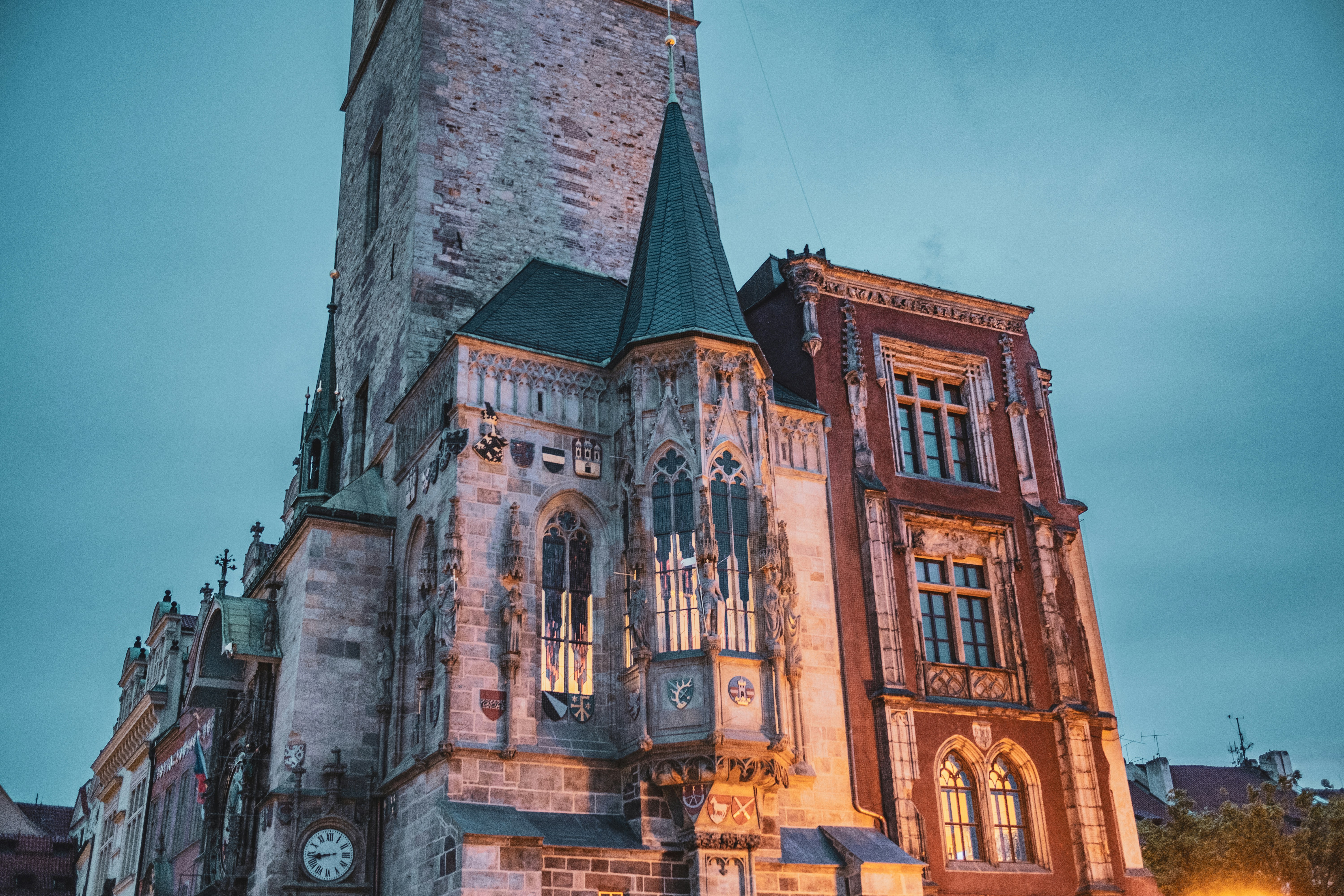 Blue-hour Gothic Facade: Warm Arches Illuminate a Turreted Brick Building