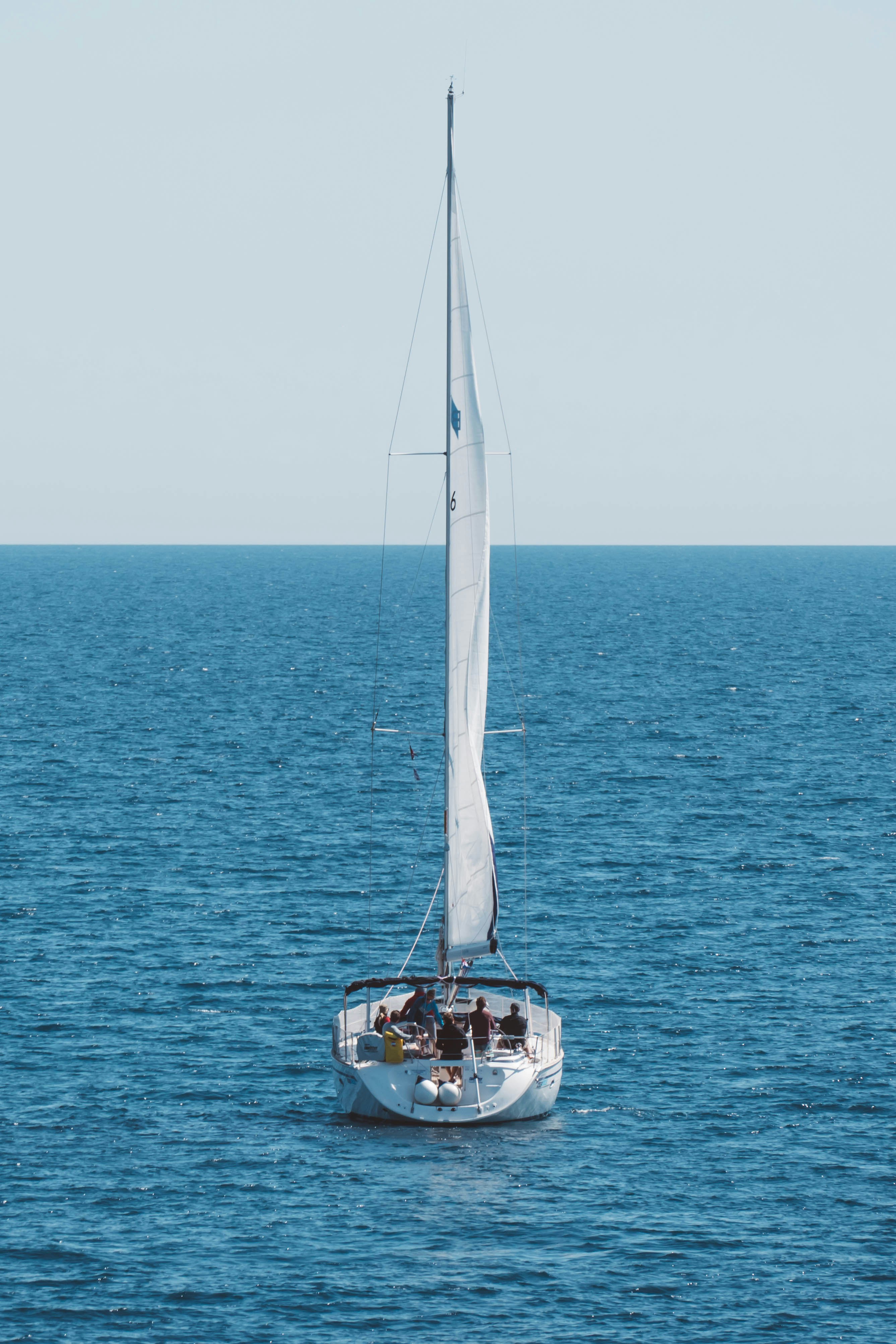 A solitary sailboat glides across a tranquil sea under a clear sky, embodying the essence of peaceful maritime adventures.