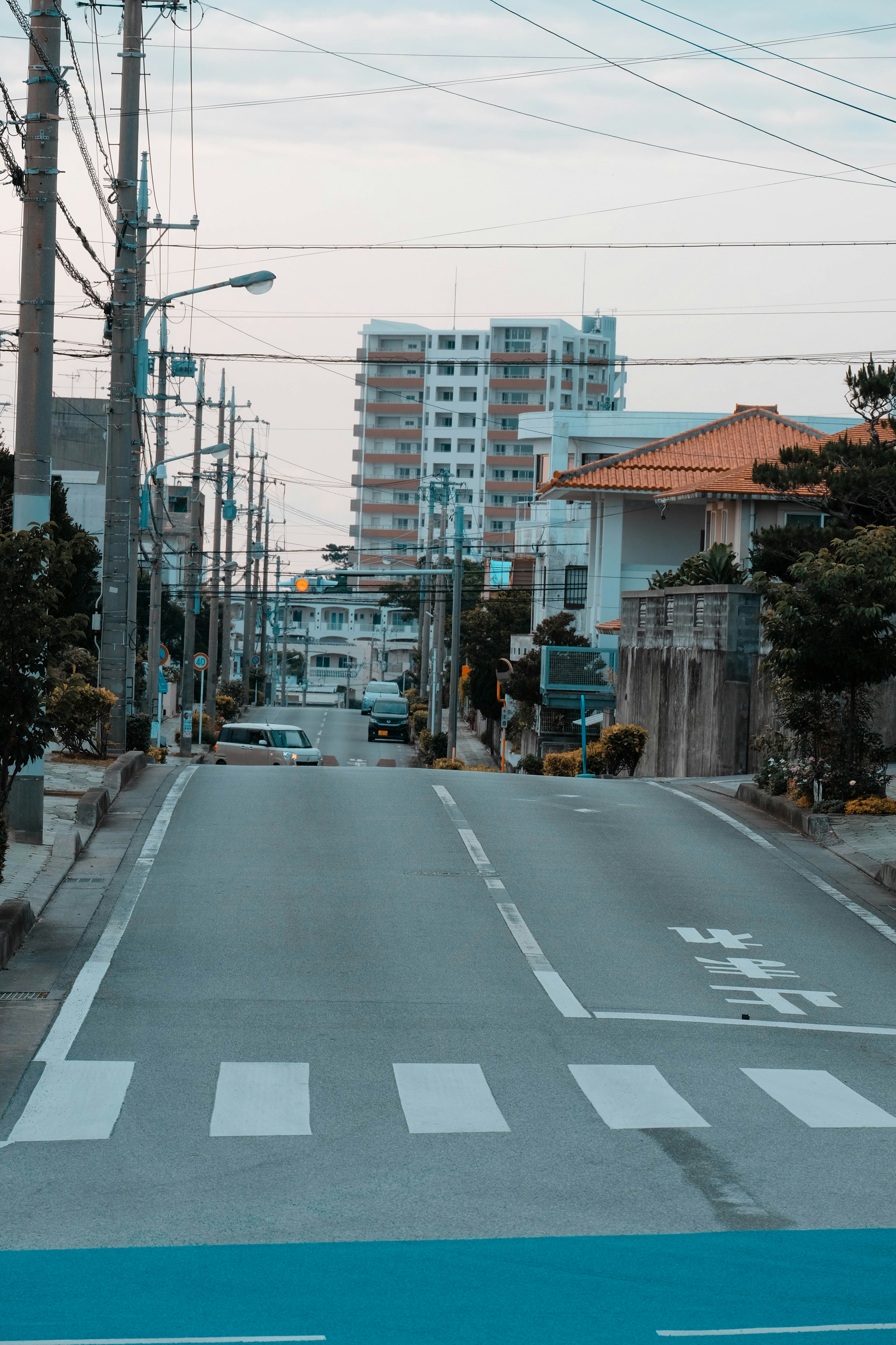 A serene urban street lined with power lines and buildings, showcasing a mix of modern and traditional architecture. The scene captures a quiet moment in the city.