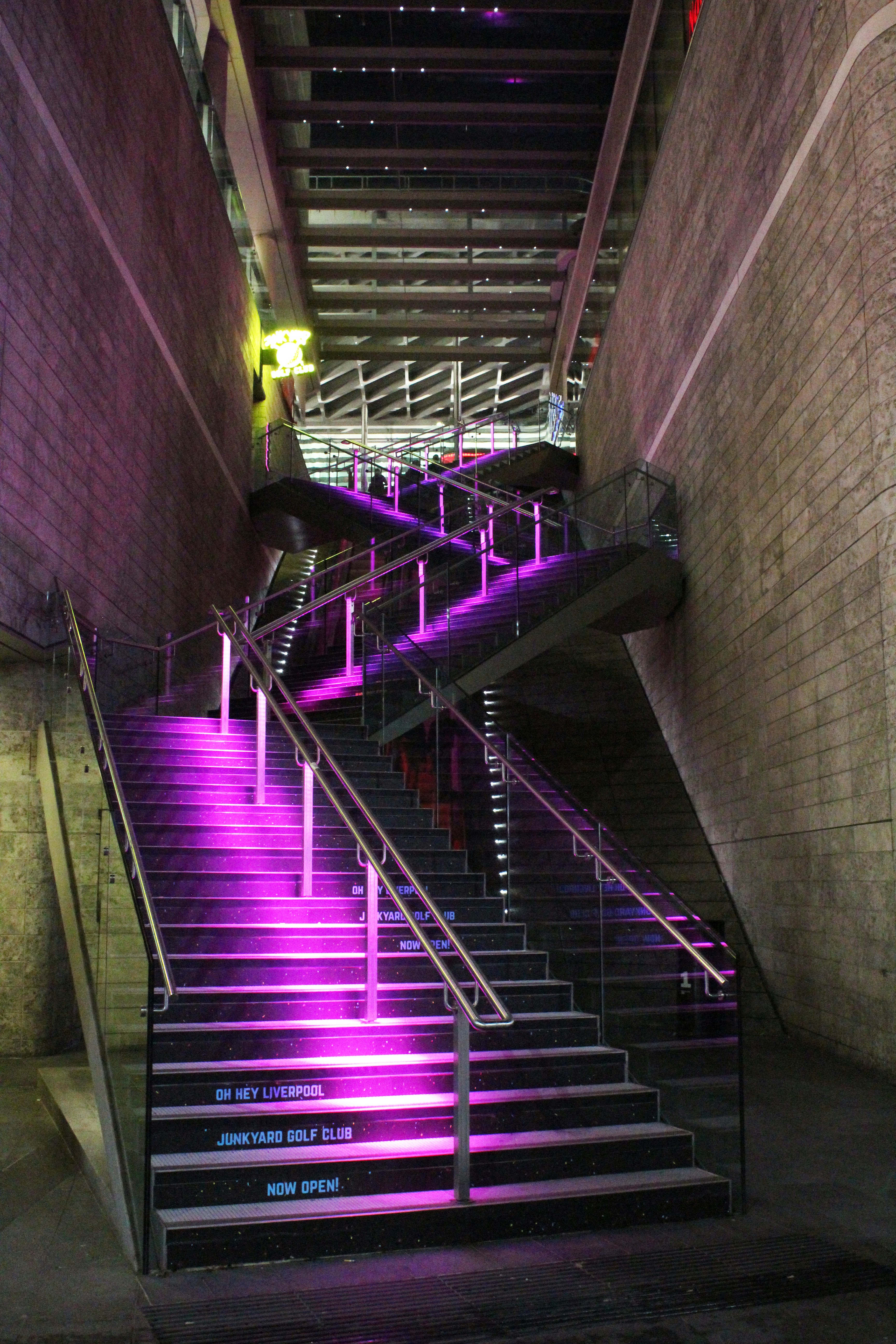 Neon Staircase: Purple Light Guides the Ascent in a Concrete Atrium