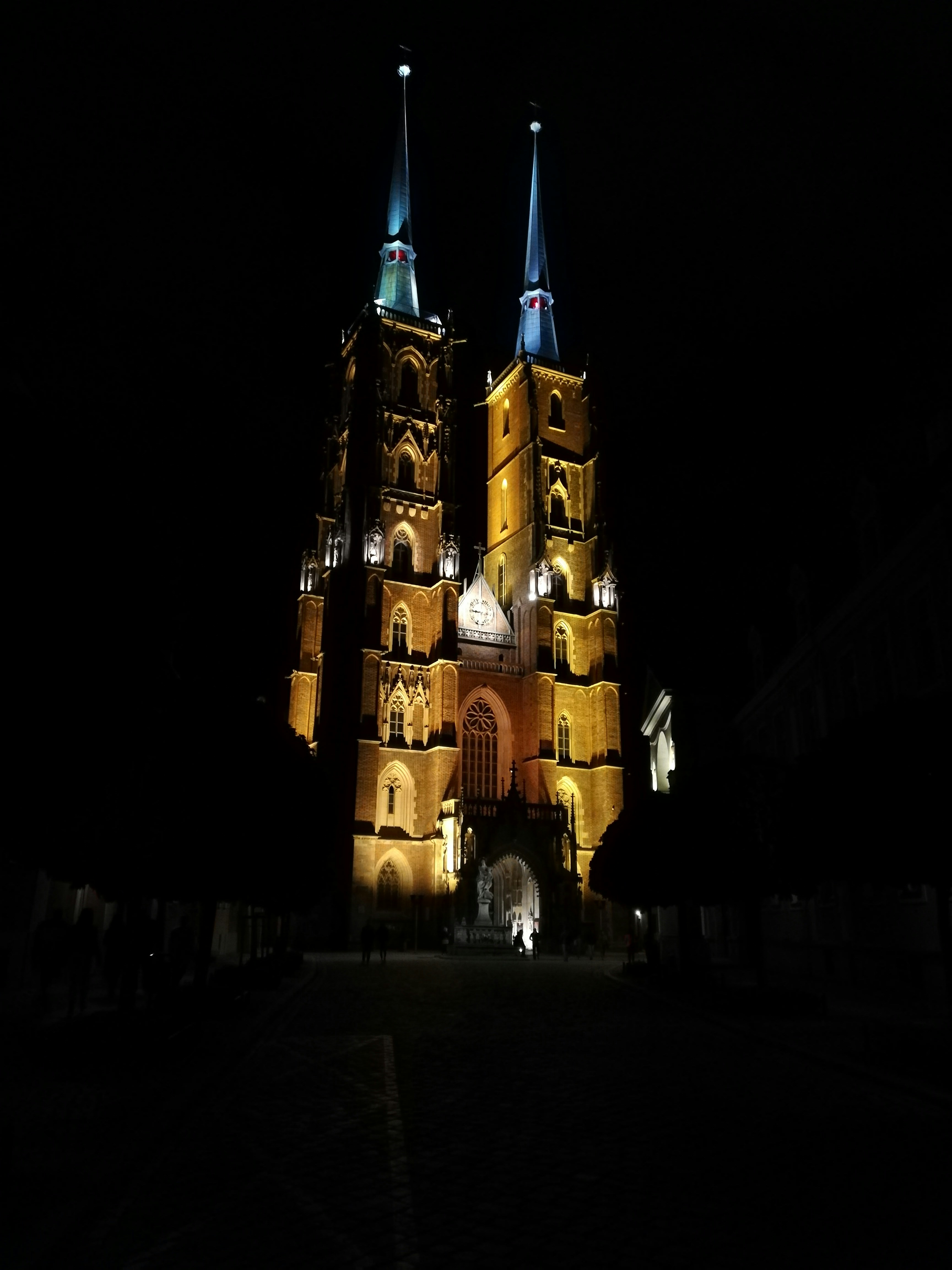 Gothic cathedral with towering spires illuminated against a dark sky, showcasing intricate architectural details and vibrant colors.