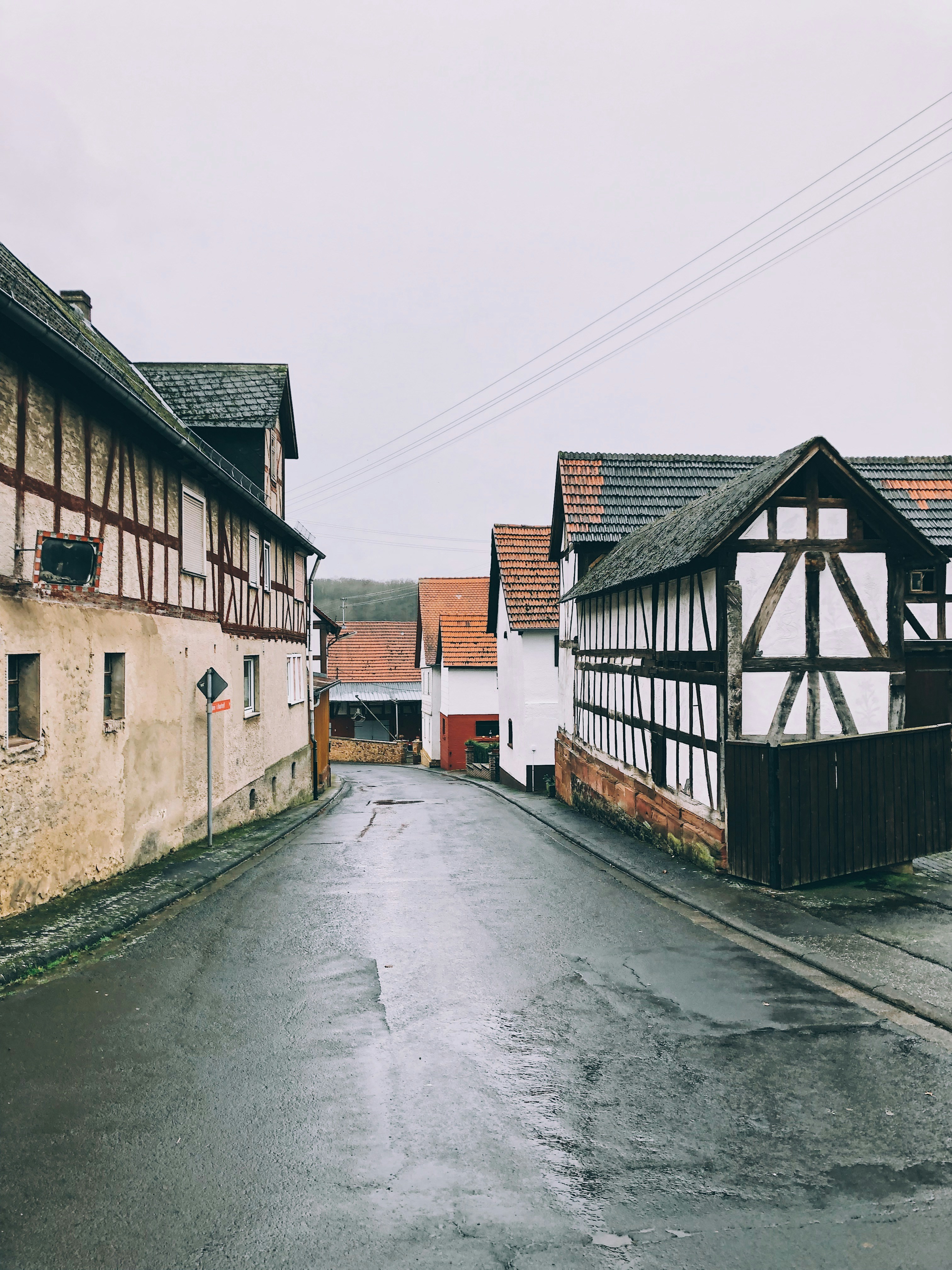 Charming village street lined with traditional half-timbered houses, reflecting a quiet, rainy day ambiance.