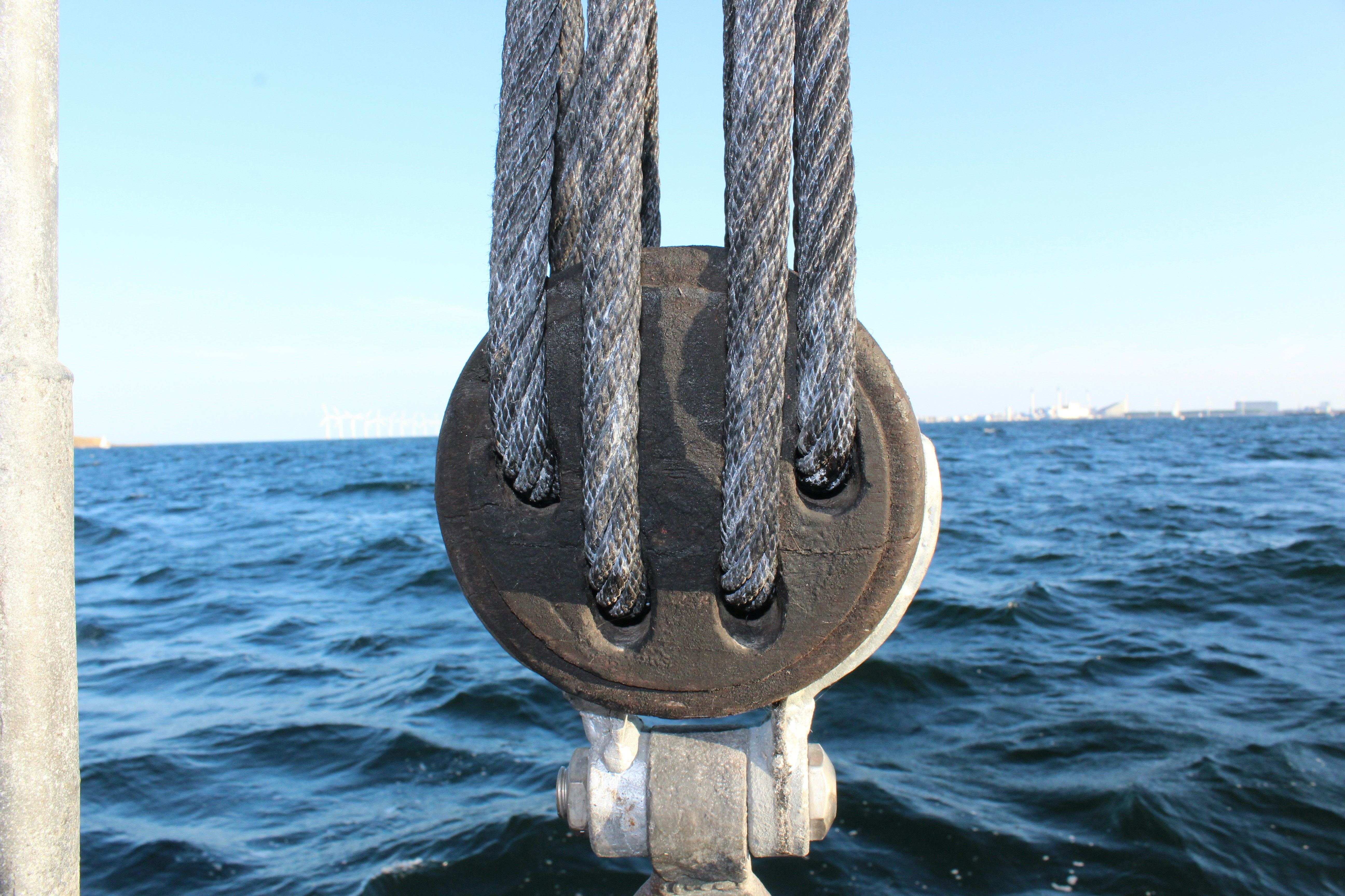 Rigging in Focus: Close-Up of a Weathered Sail Pulley Against the Sea