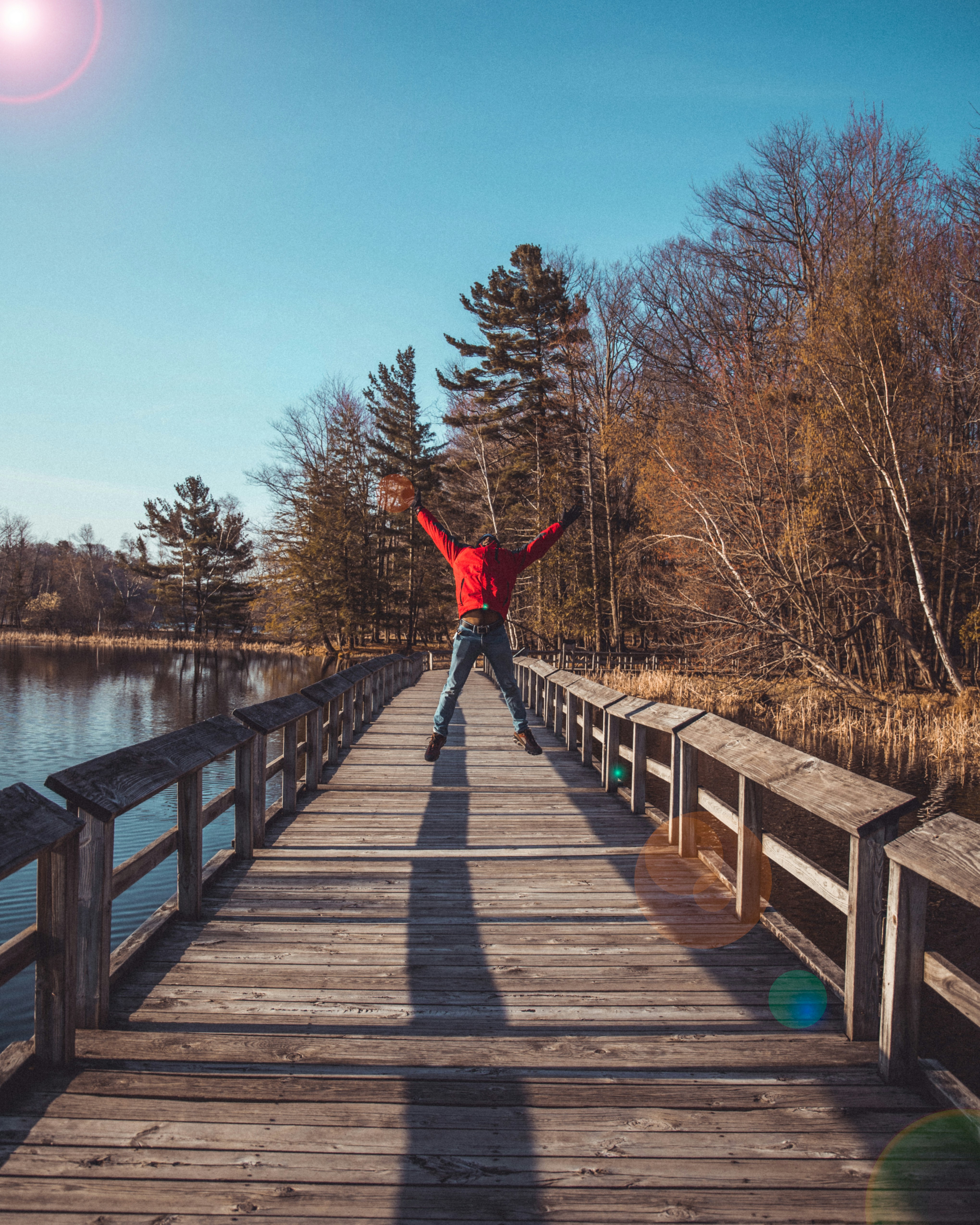 Man in red jacket leaps on air at the wooden walk bridge photo – Free ...