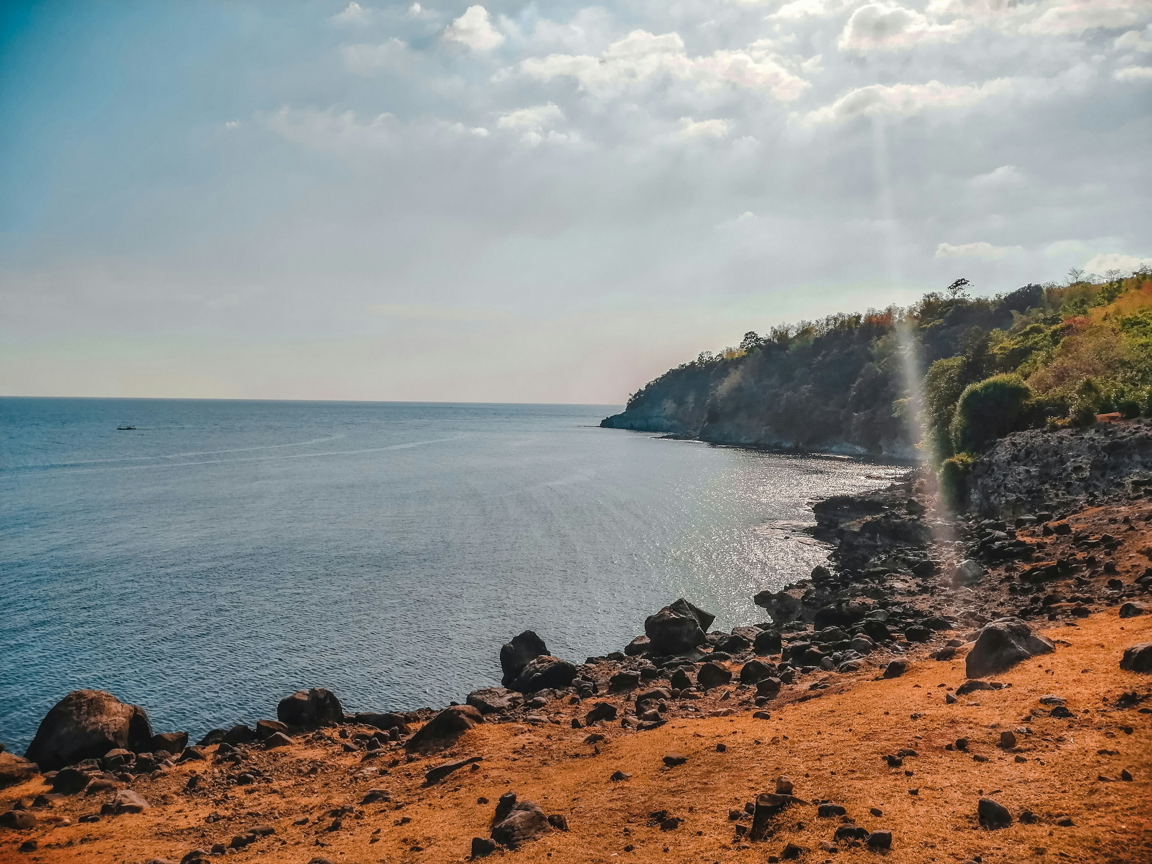 Rocky shoreline meeting calm ocean under a partly cloudy sky.
