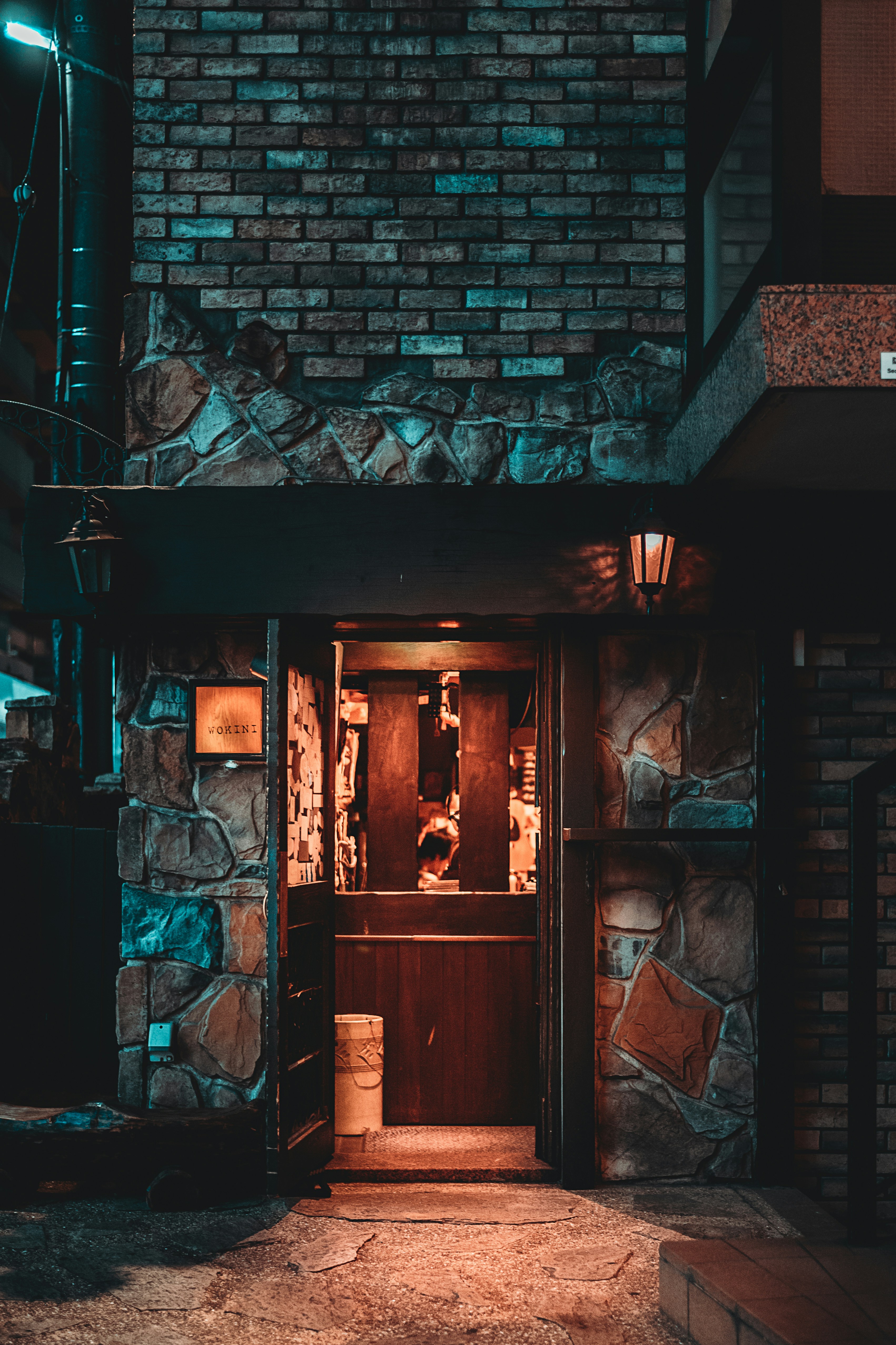 Inviting entrance of a cozy establishment, illuminated by warm light, with stone and wood textures creating a rustic ambiance.