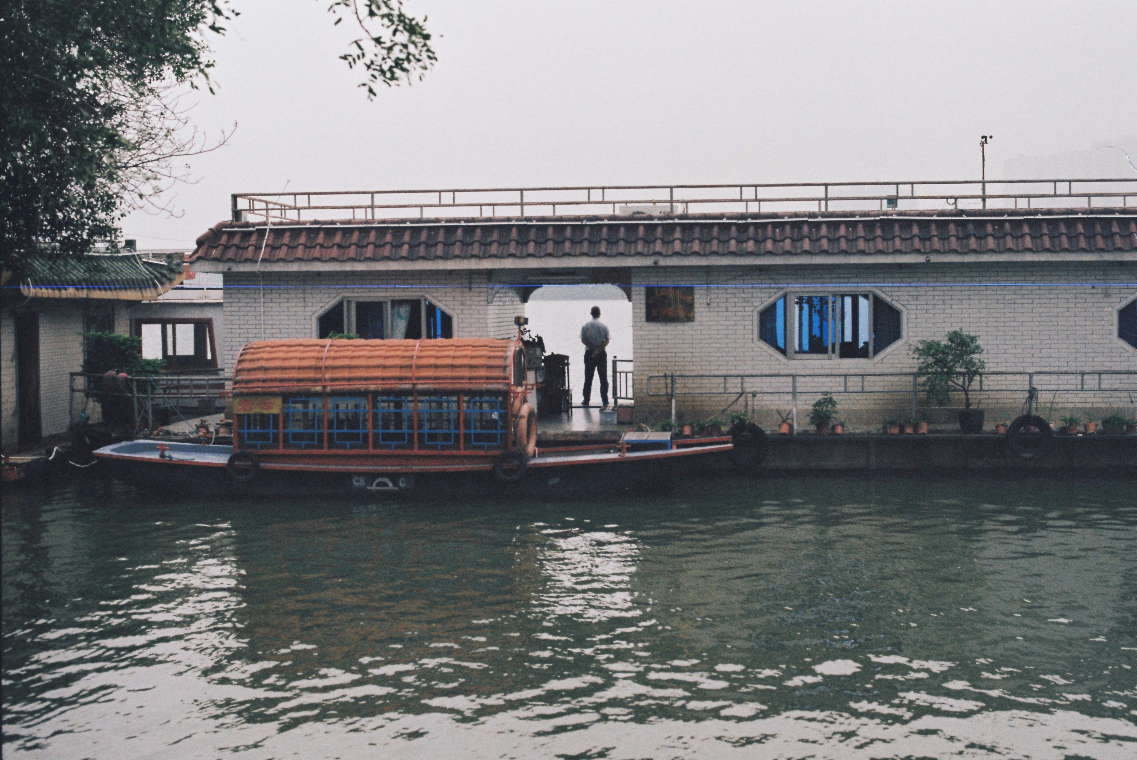 Canalside Reverie: Figures on a Roofed Houseboat