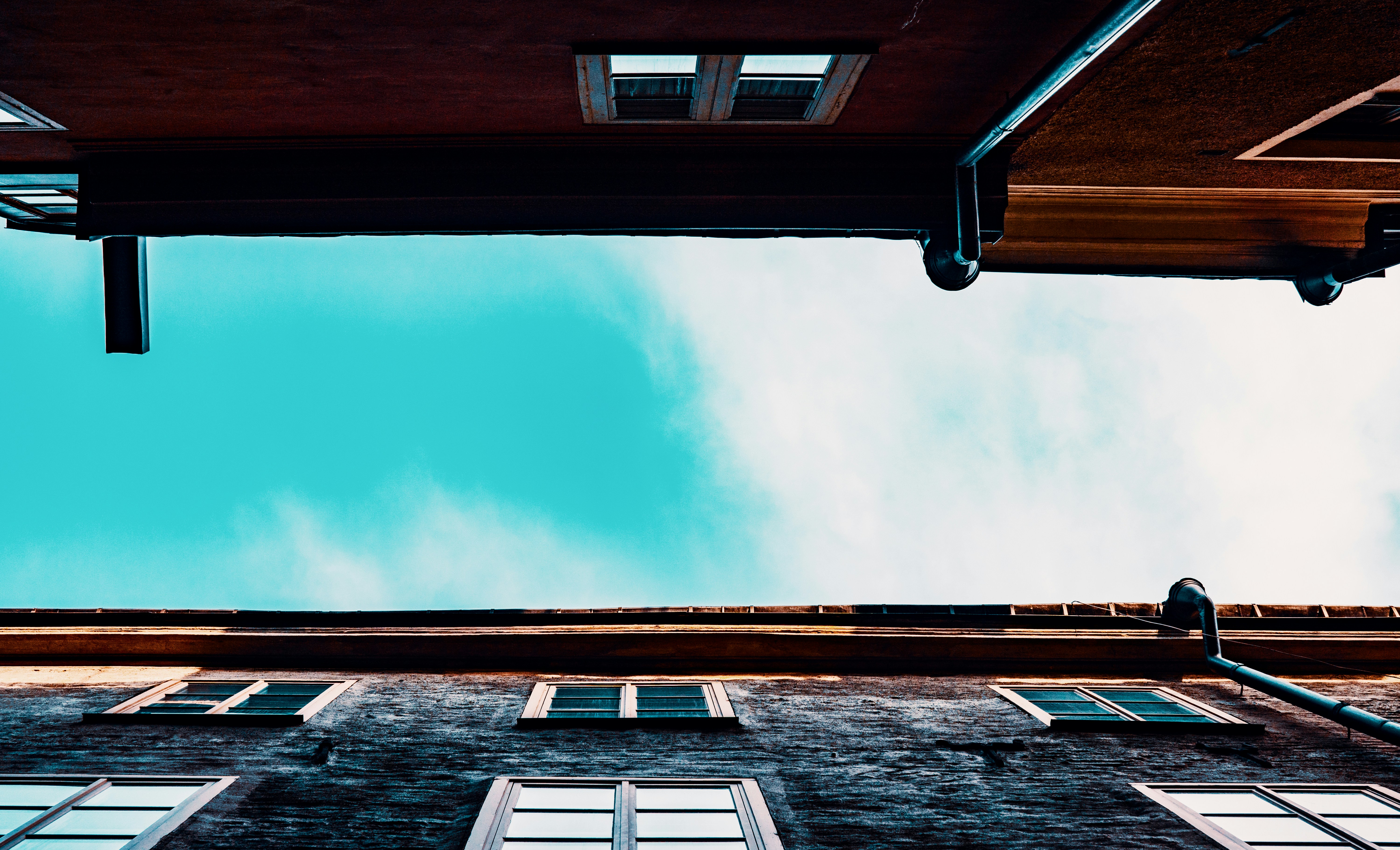 View of buildings converging towards a bright sky, showcasing architectural lines and contrasting colors.