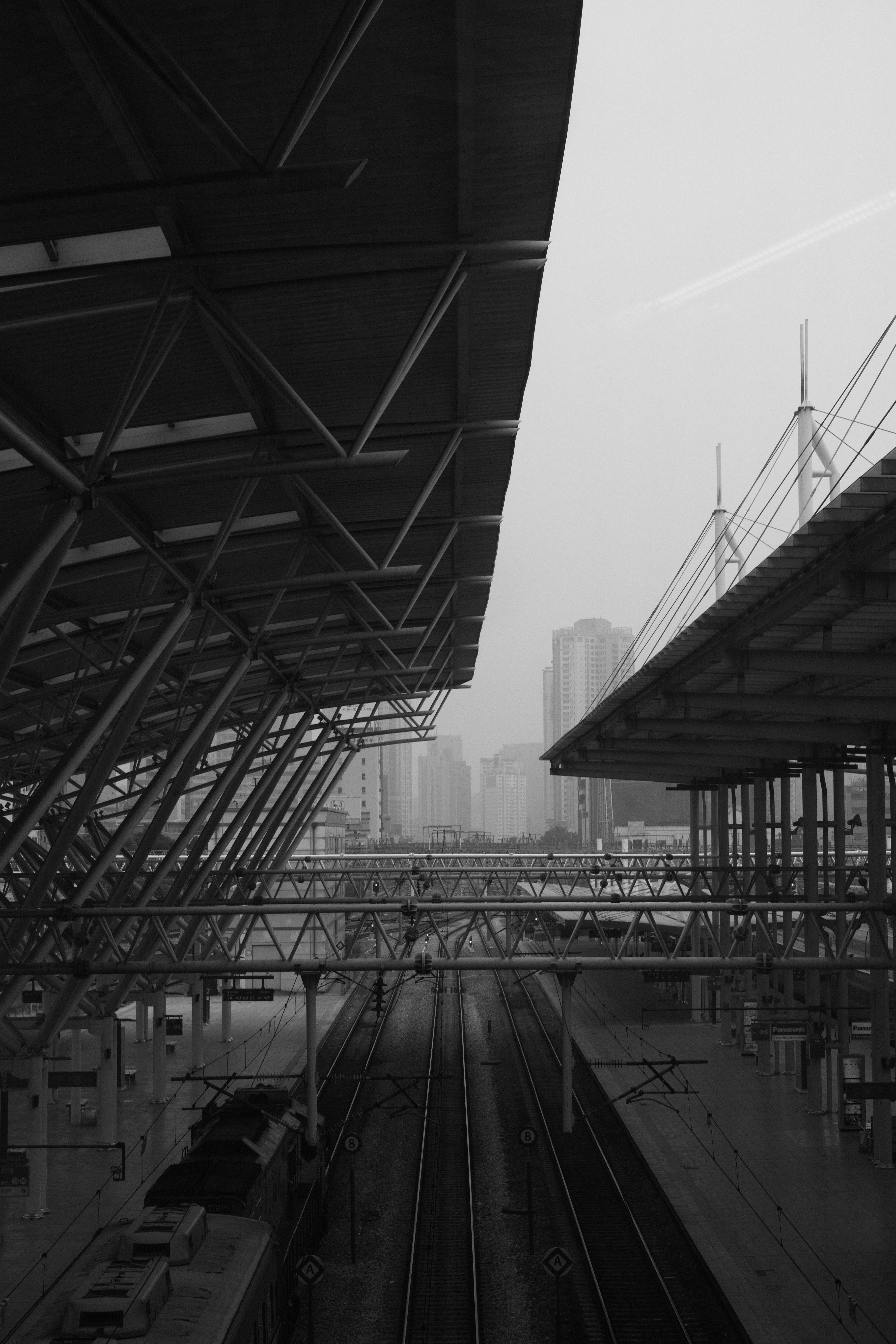 Modern train station architecture showcasing intricate steel structures and railway tracks leading into the distance.