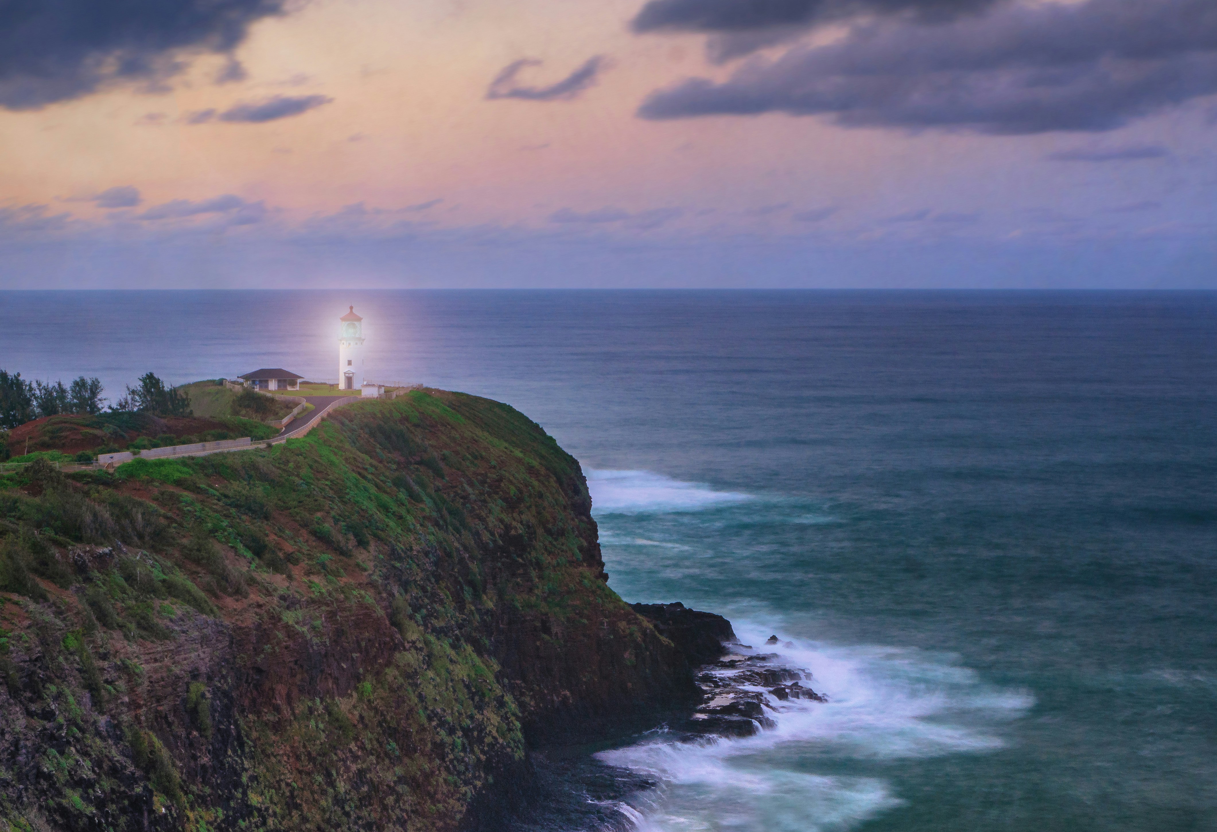 Lighthouse turned on on top of island mountain during golden hour photo ...