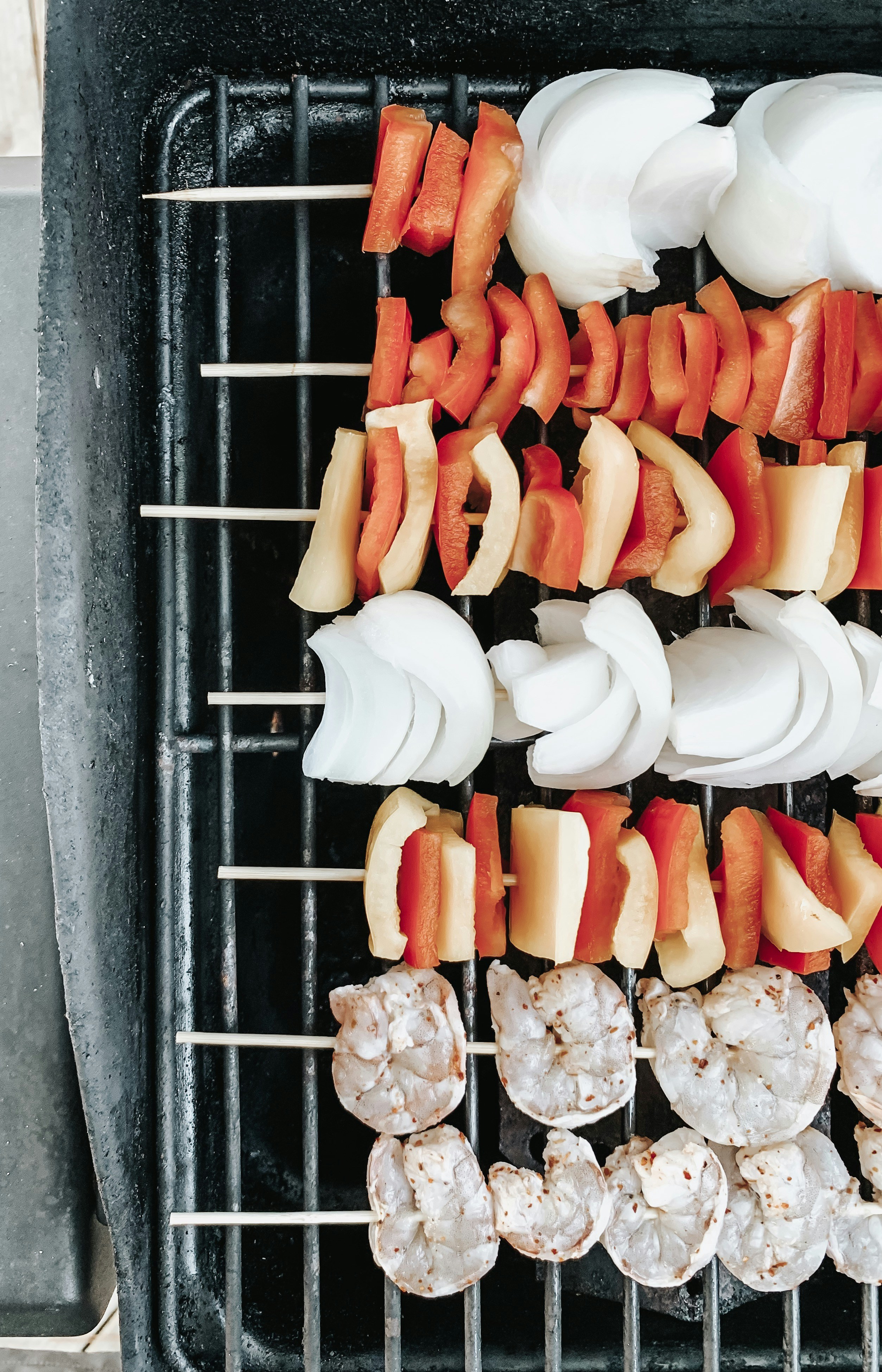 Colorful skewers of shrimp and bell peppers arranged on a grill, showcasing a vibrant mix of fresh ingredients ready for cooking.