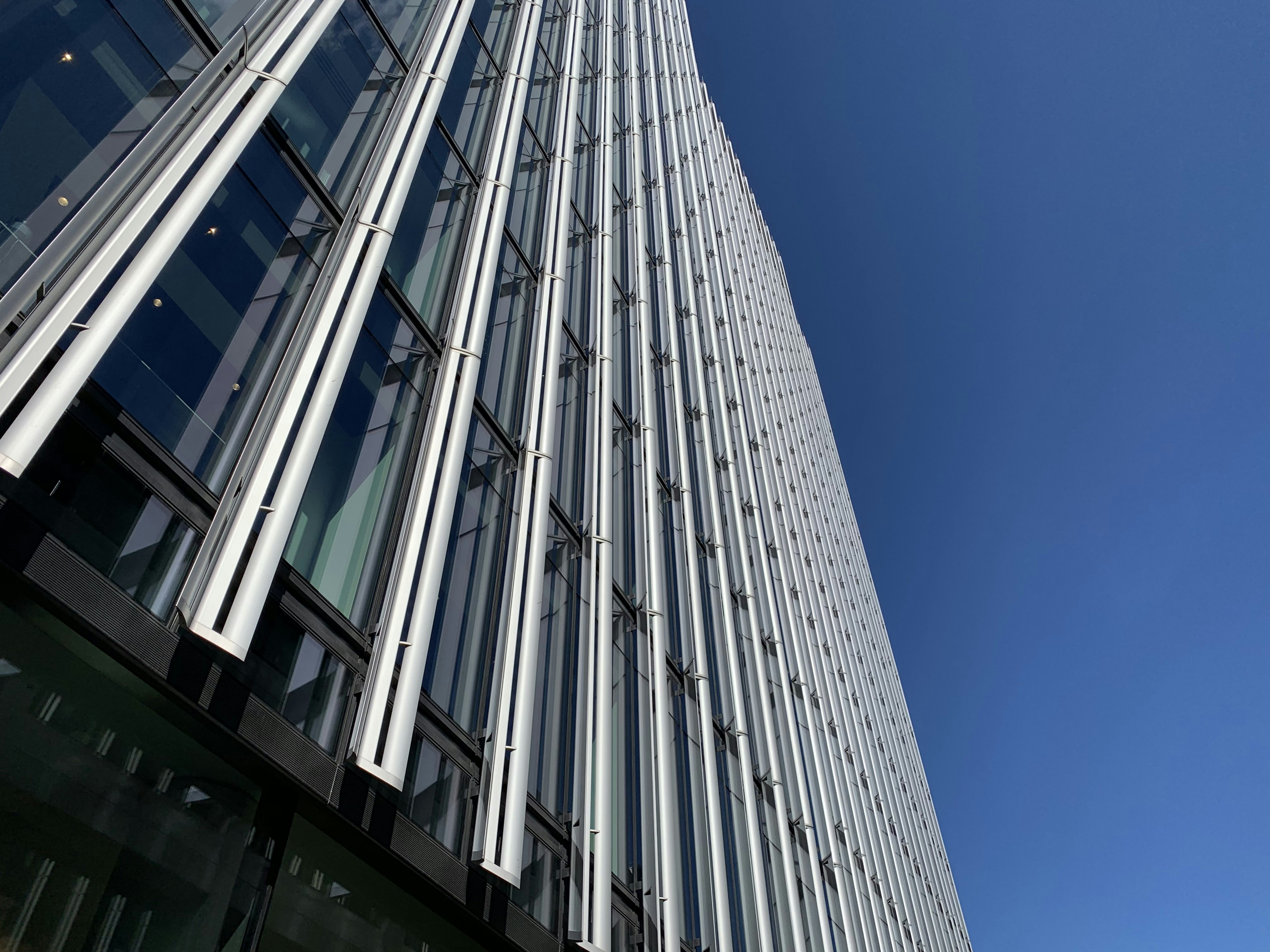 High-rise building with sleek glass and metal facade against a clear blue sky.