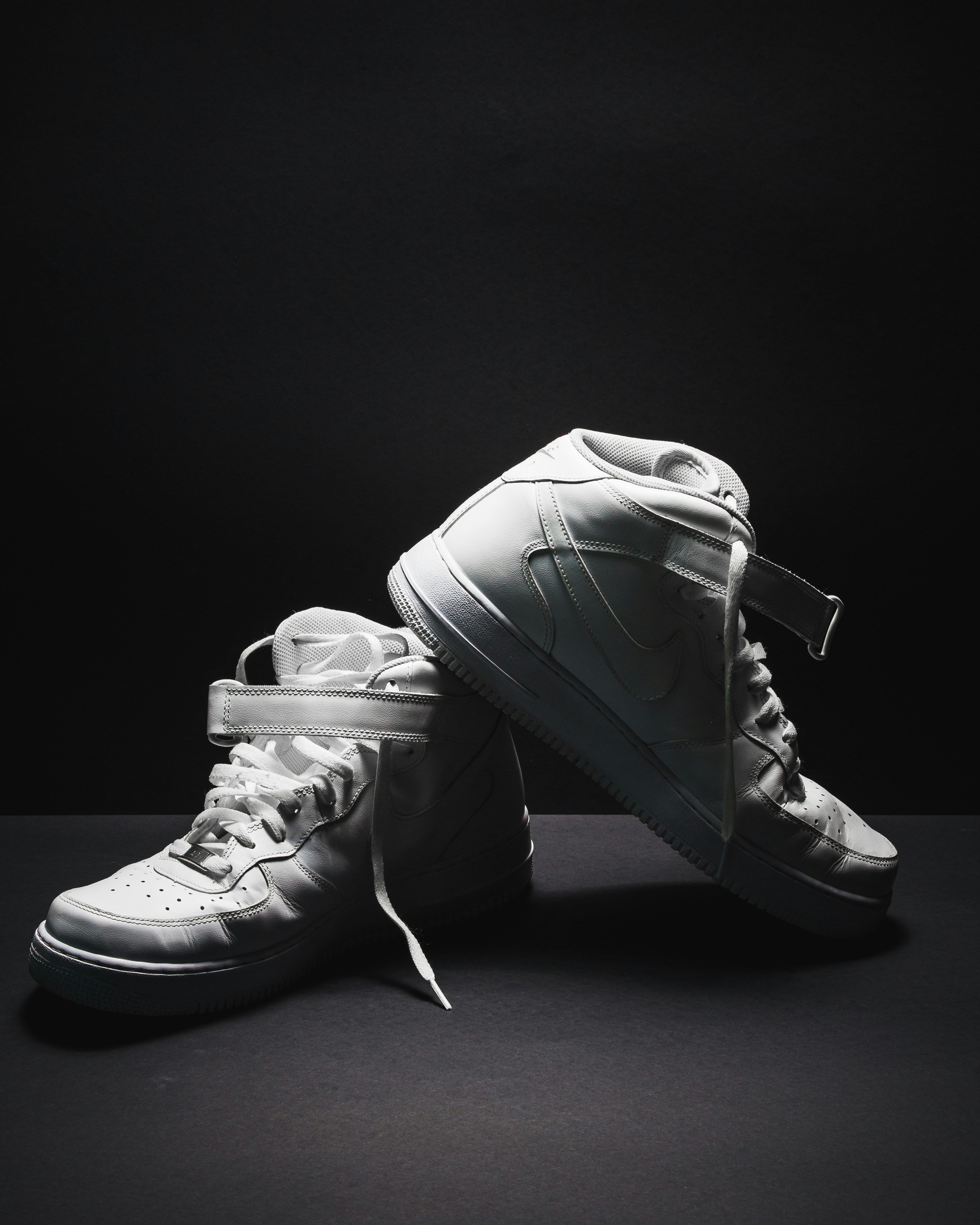 White high-top sneakers artfully positioned against a dark background, highlighting their sleek design and details.