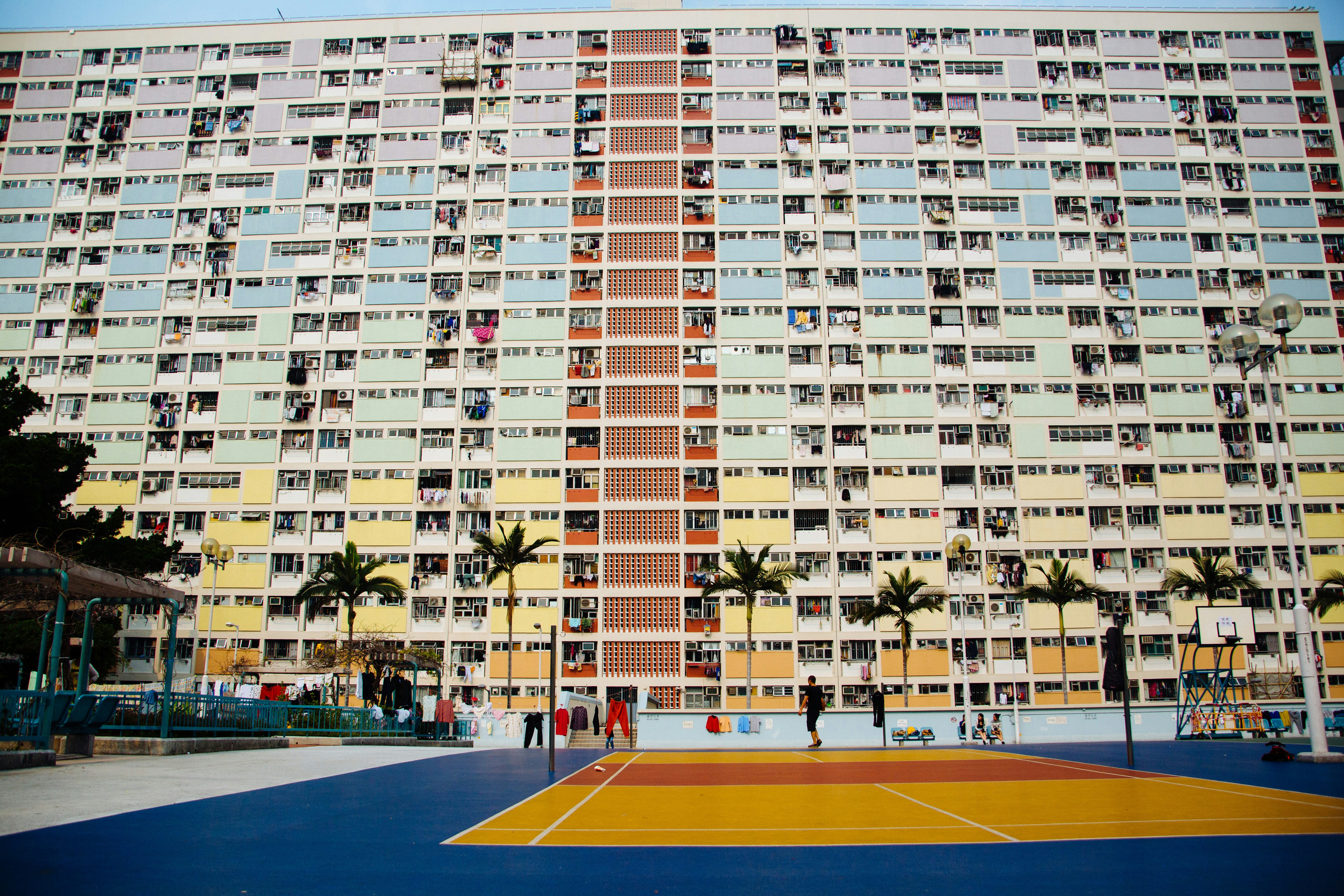 Vibrant basketball court set against a backdrop of a multi-colored residential building, showcasing urban life and recreational space.