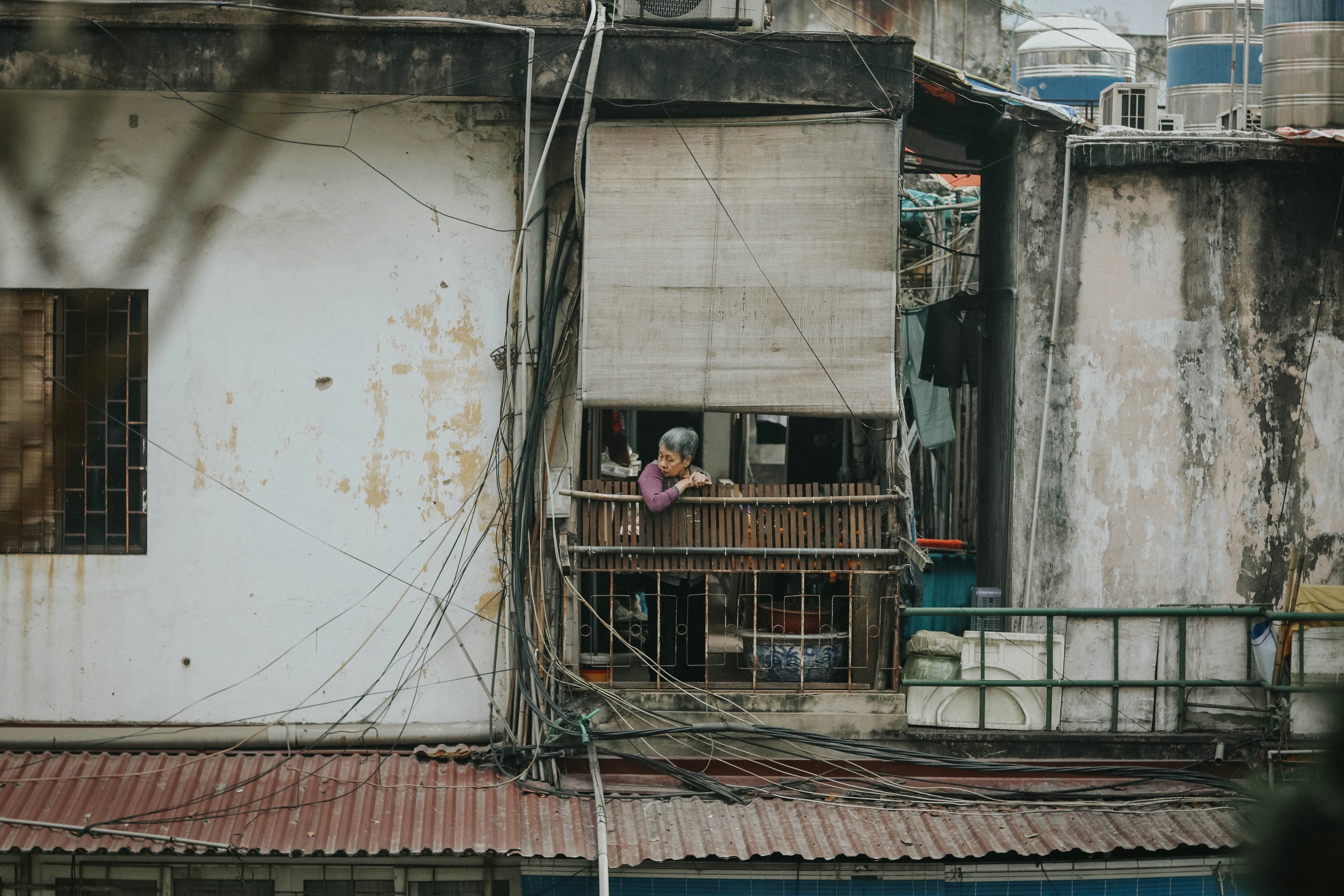 Person leaning out of a rustic, weathered building window in an urban setting.