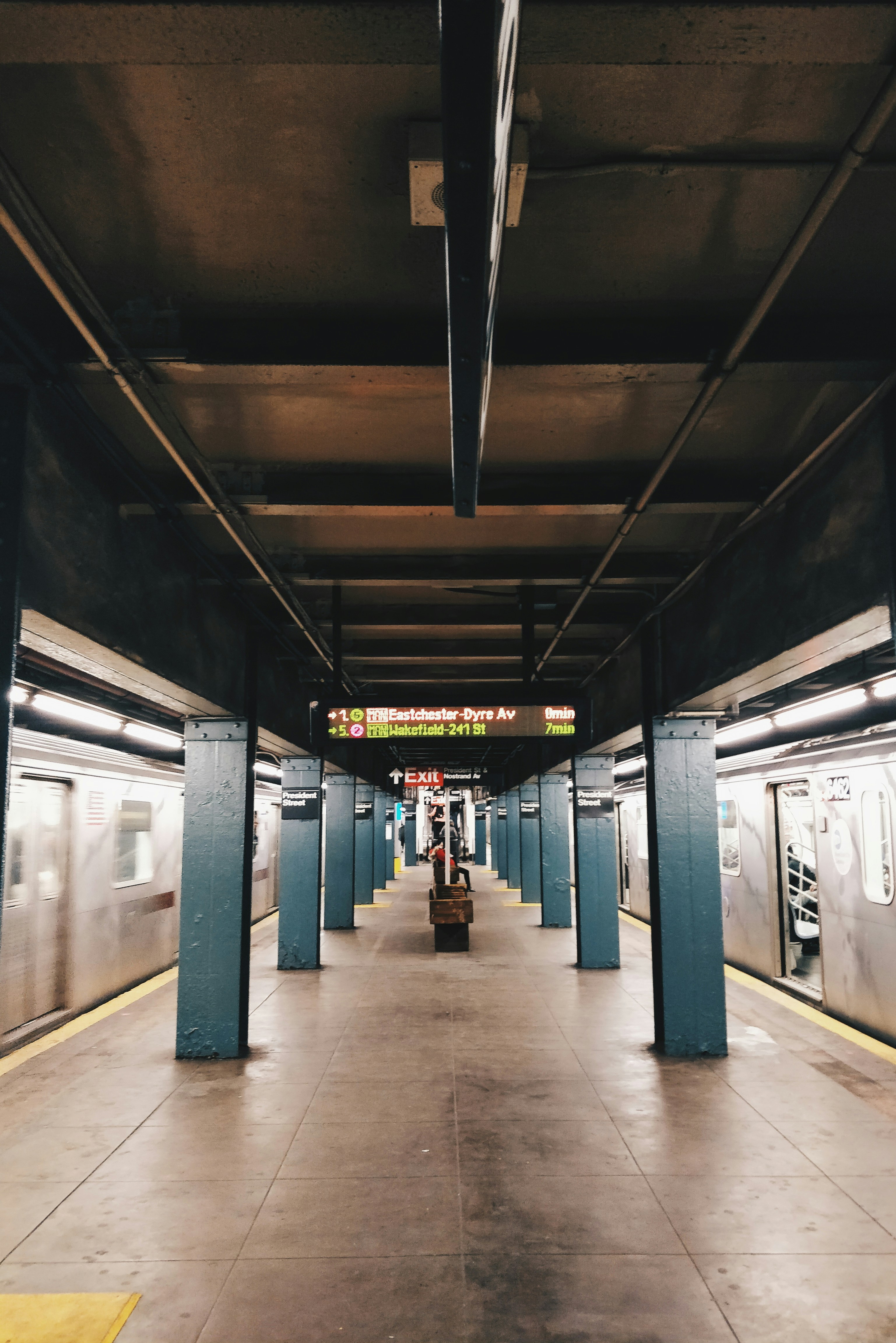 Subway platform featuring illuminated signs showing train arrival times and empty benches, conveying the essence of urban commuting.