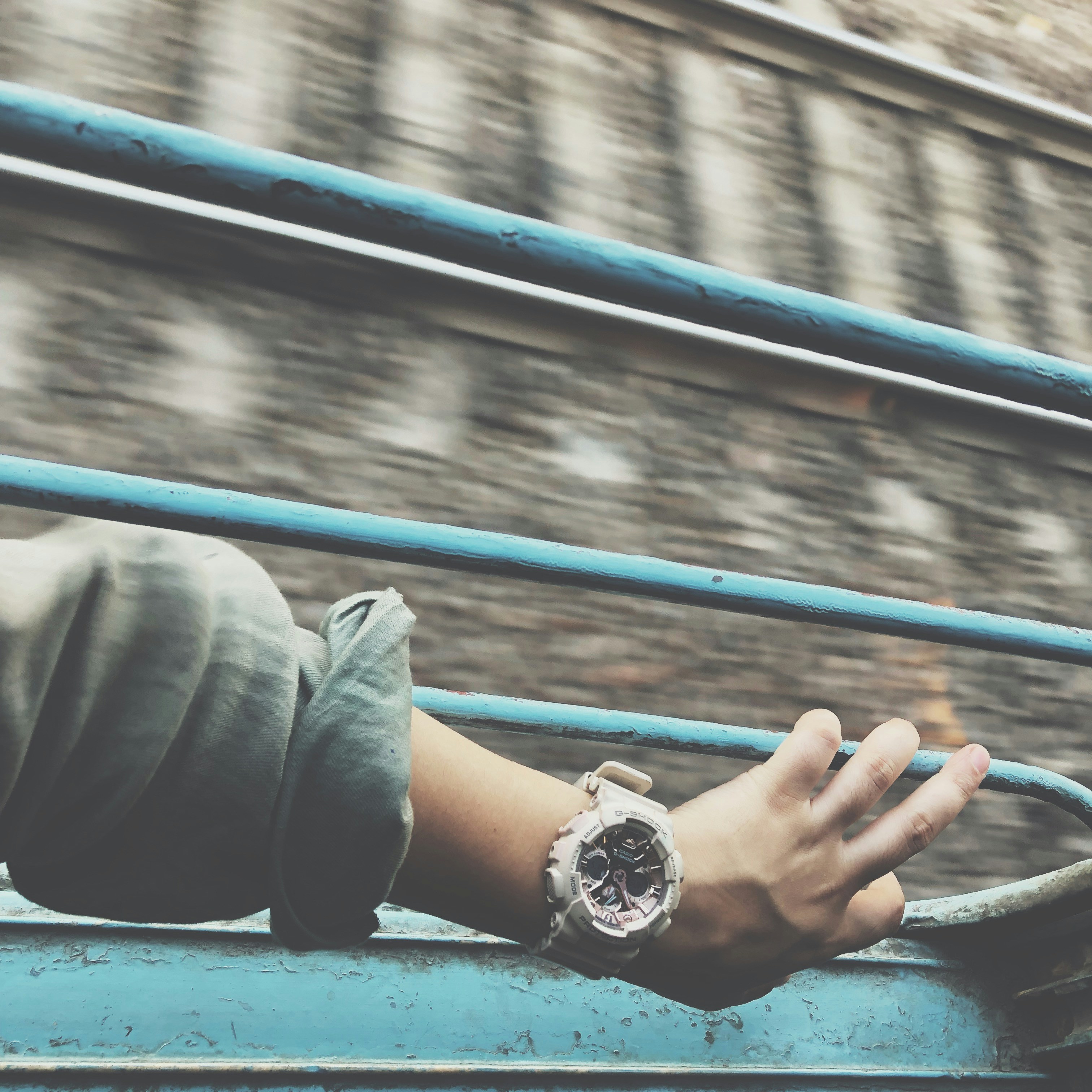 Blue Railings, Worn Timer: A Casual Wrist on the City’s Edge