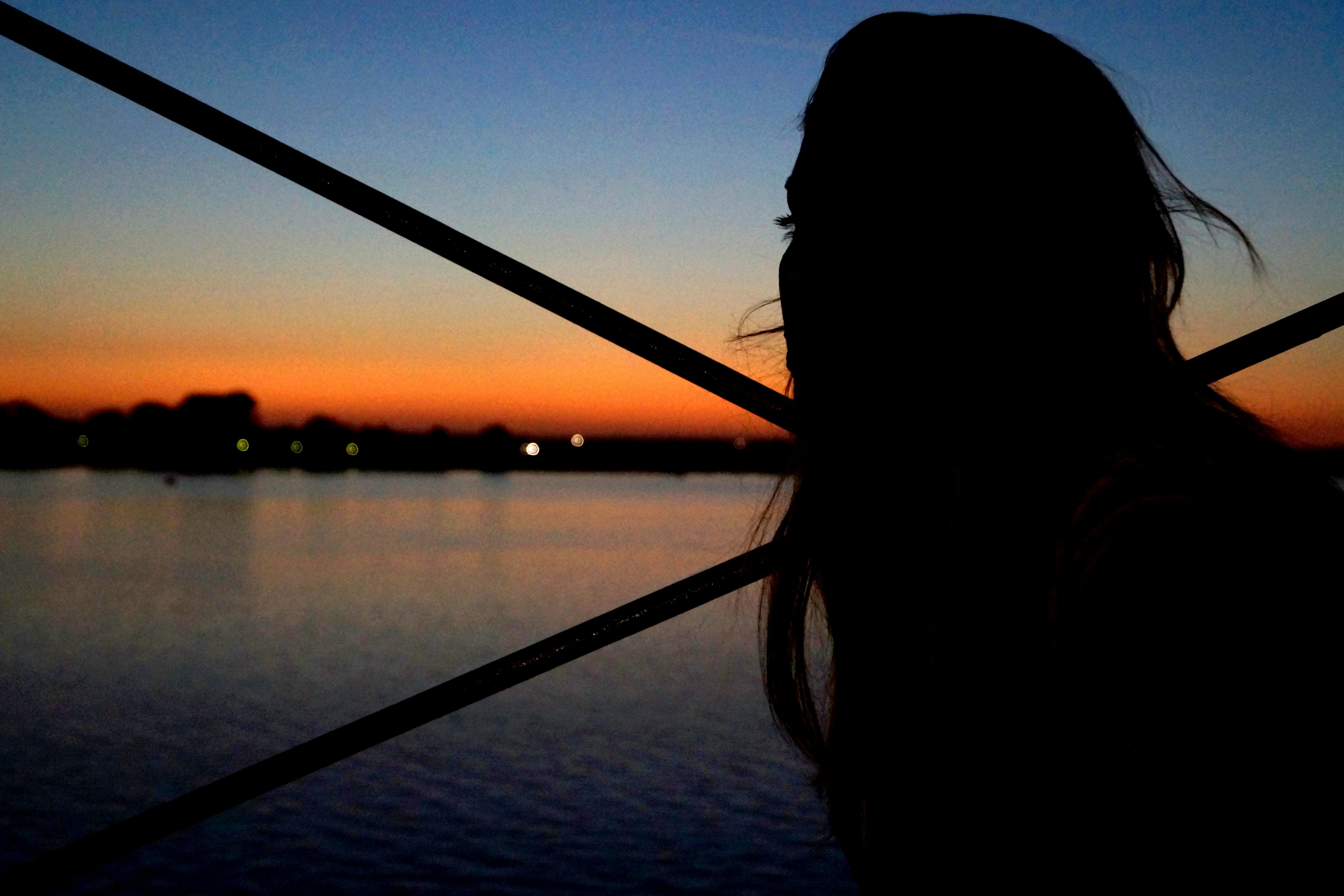 Silhouette of a person against a vibrant sunset over a calm lake.