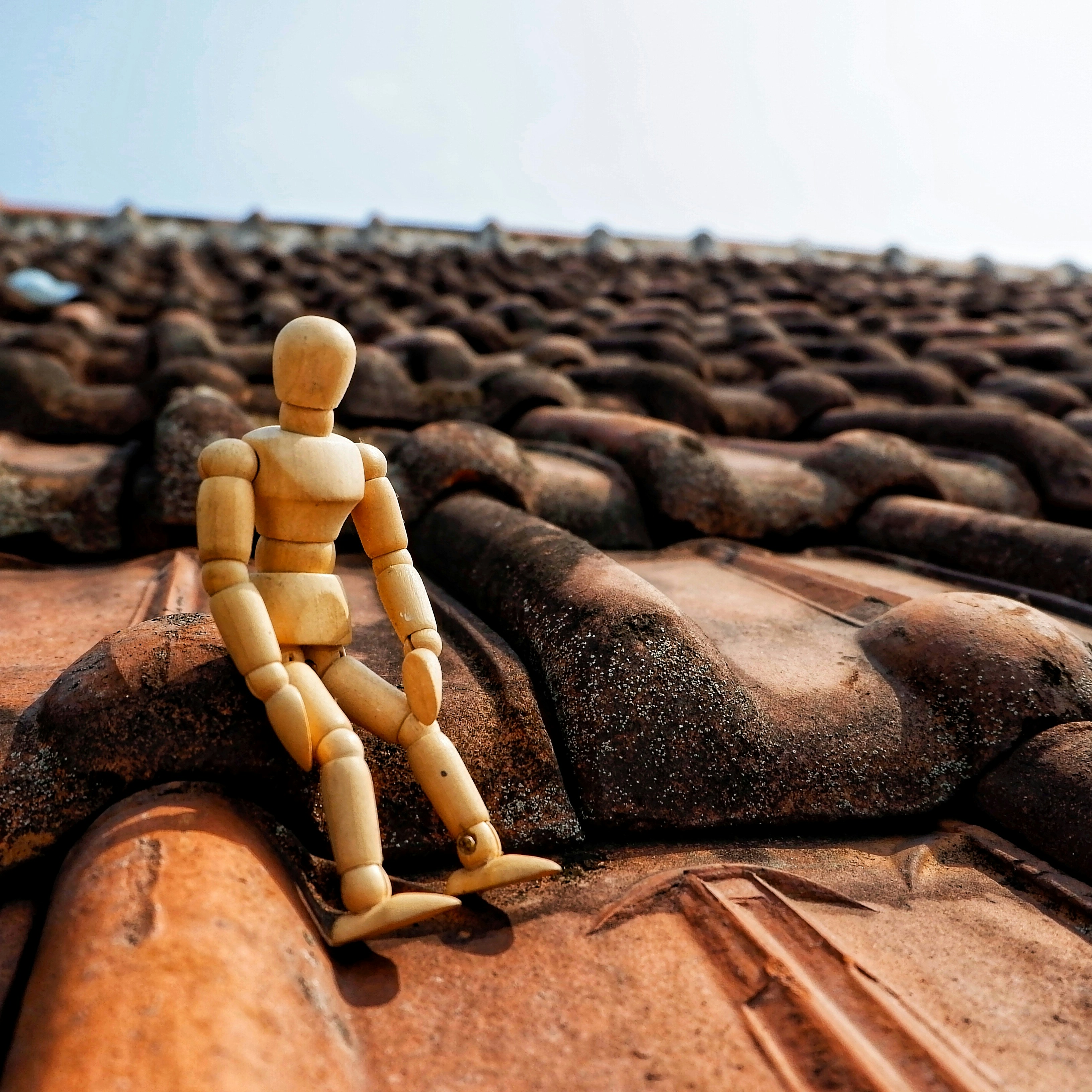 Lone Wooden Figure on Timeworn Roof Tiles