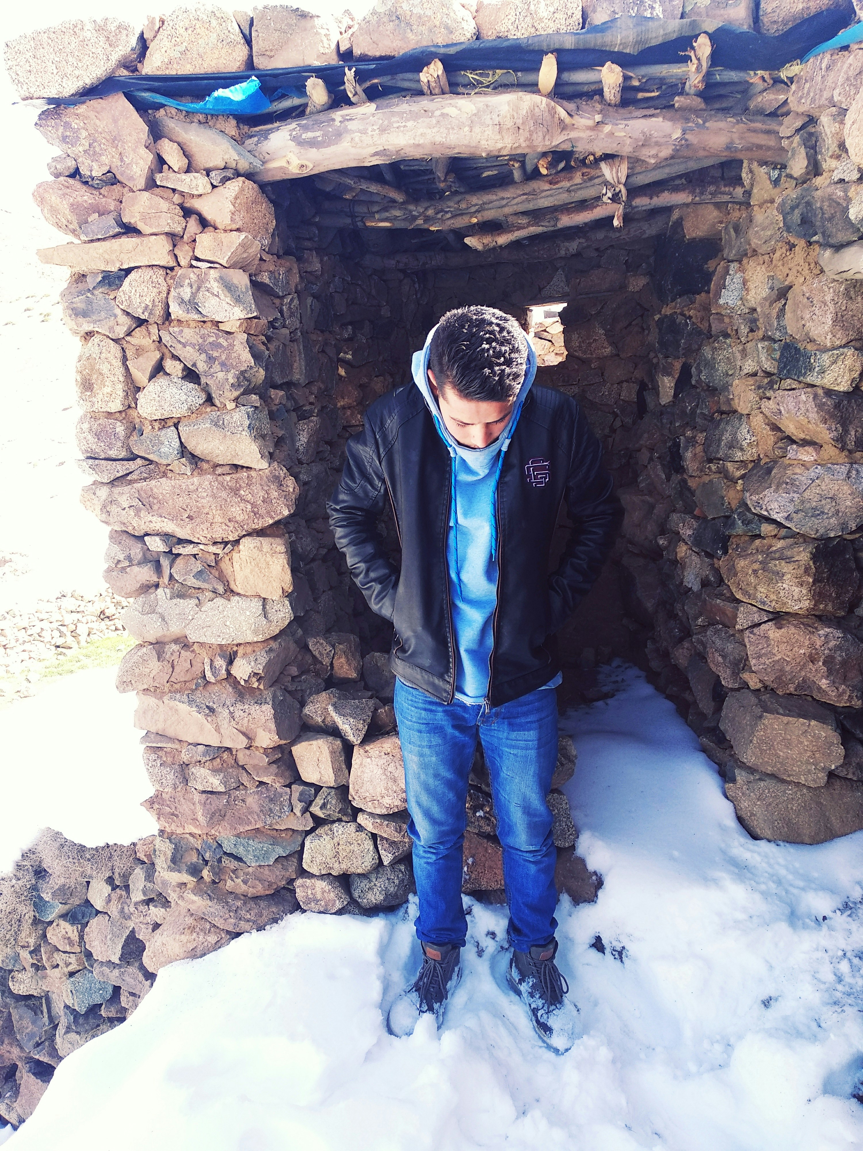 Winter Threshold in a Stone Passage: A Hoodie-Clad Figure Anchored by Rough Walls
