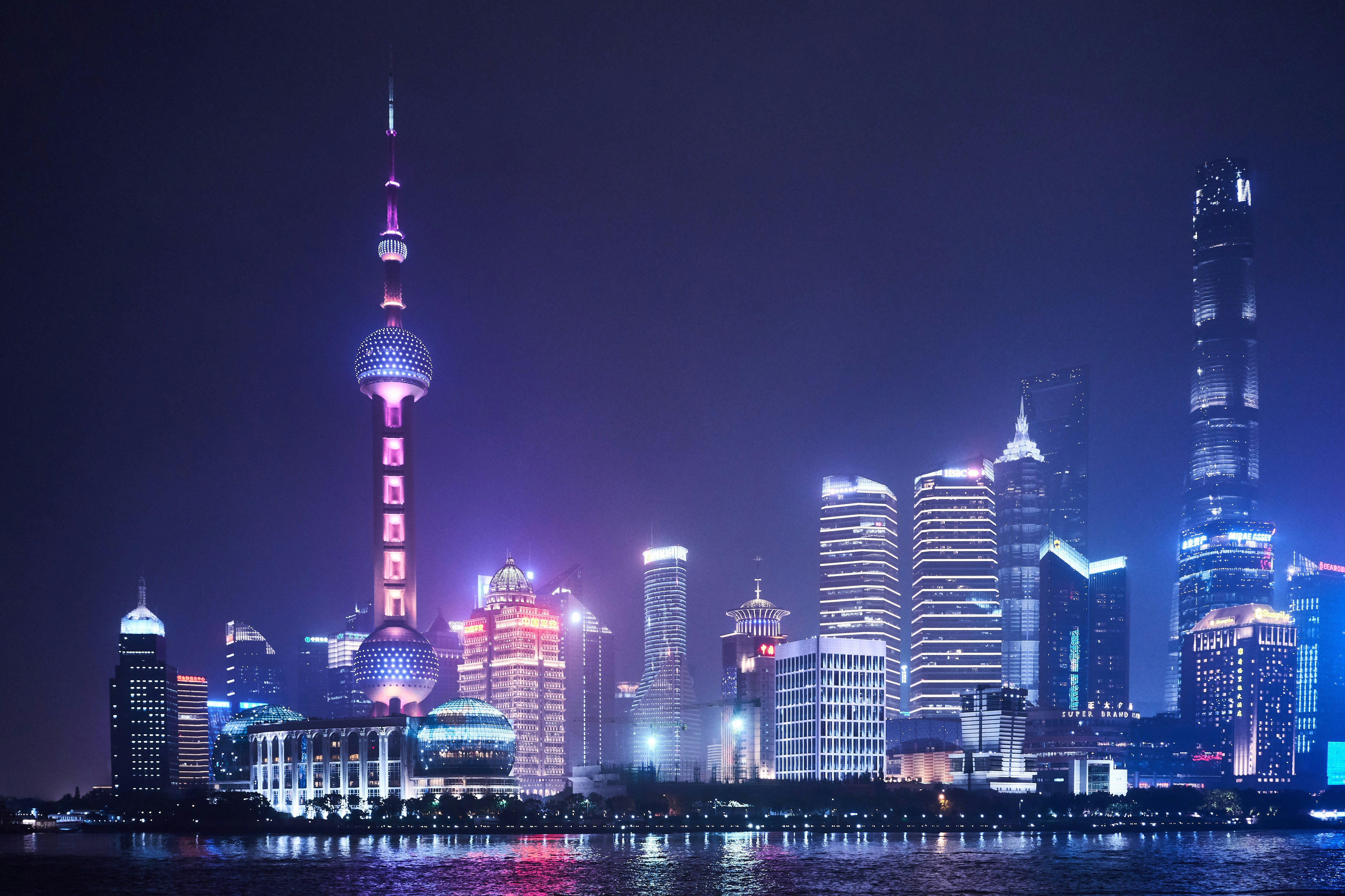 Illuminated Shanghai skyline with vibrant neon lights and the iconic Oriental Pearl Tower against a night sky.
