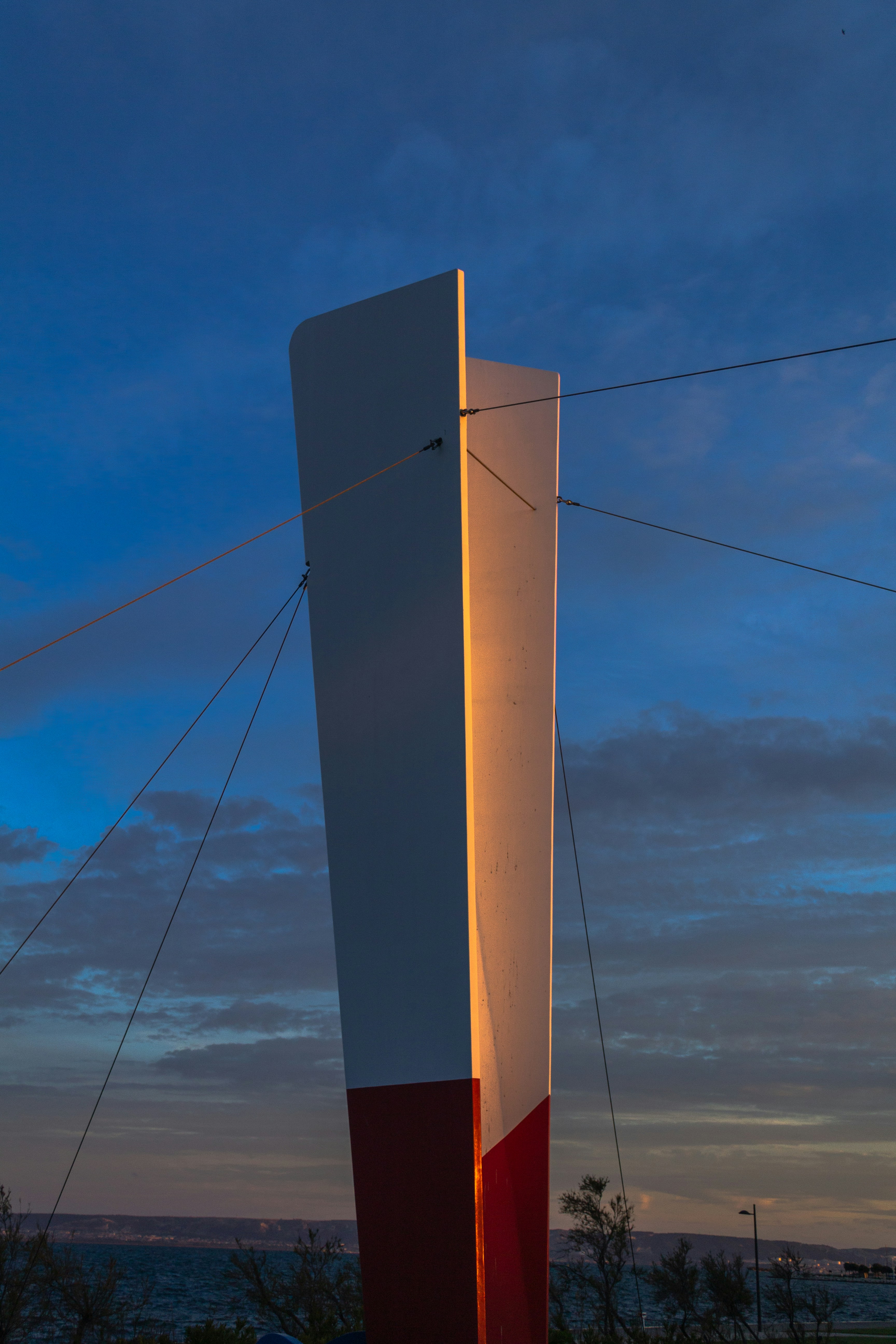 Sunlit Edge of a Cable-Supported Tower at Blue Hour by the Sea