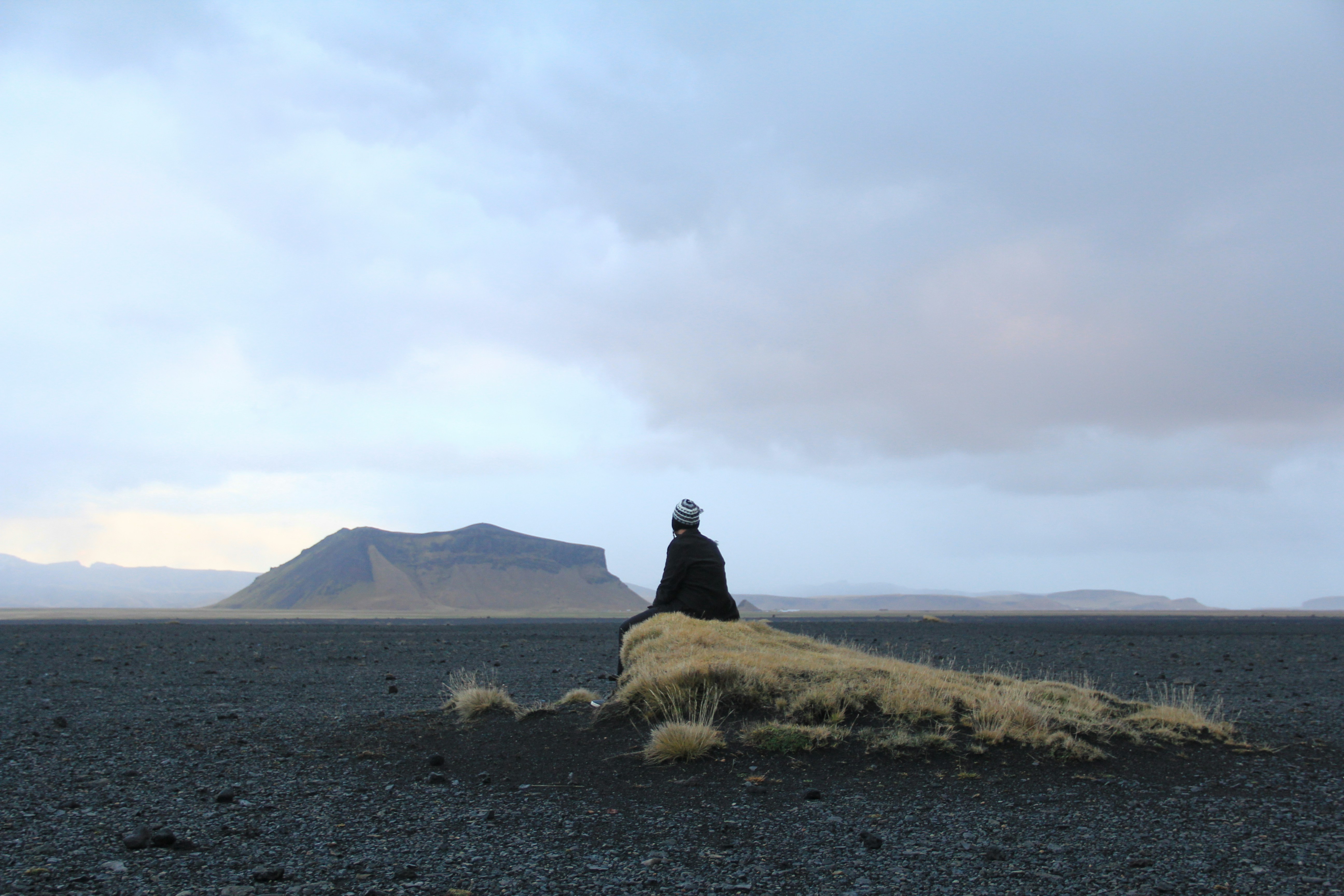  lone observer on a weathered outcrop facing a distant shoreline