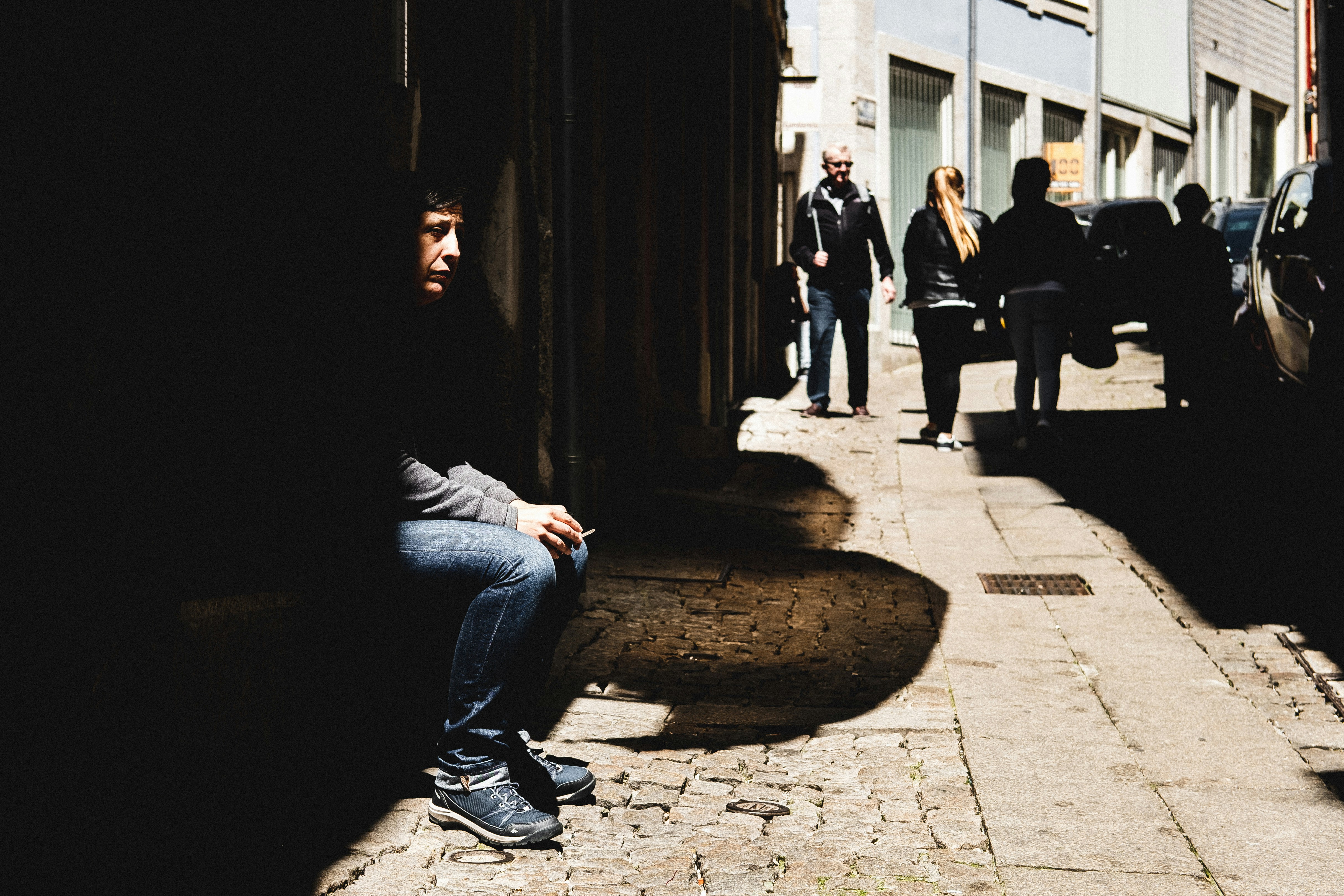 Shadowed Threshold: A Quiet Figure Framed by a Busier Street