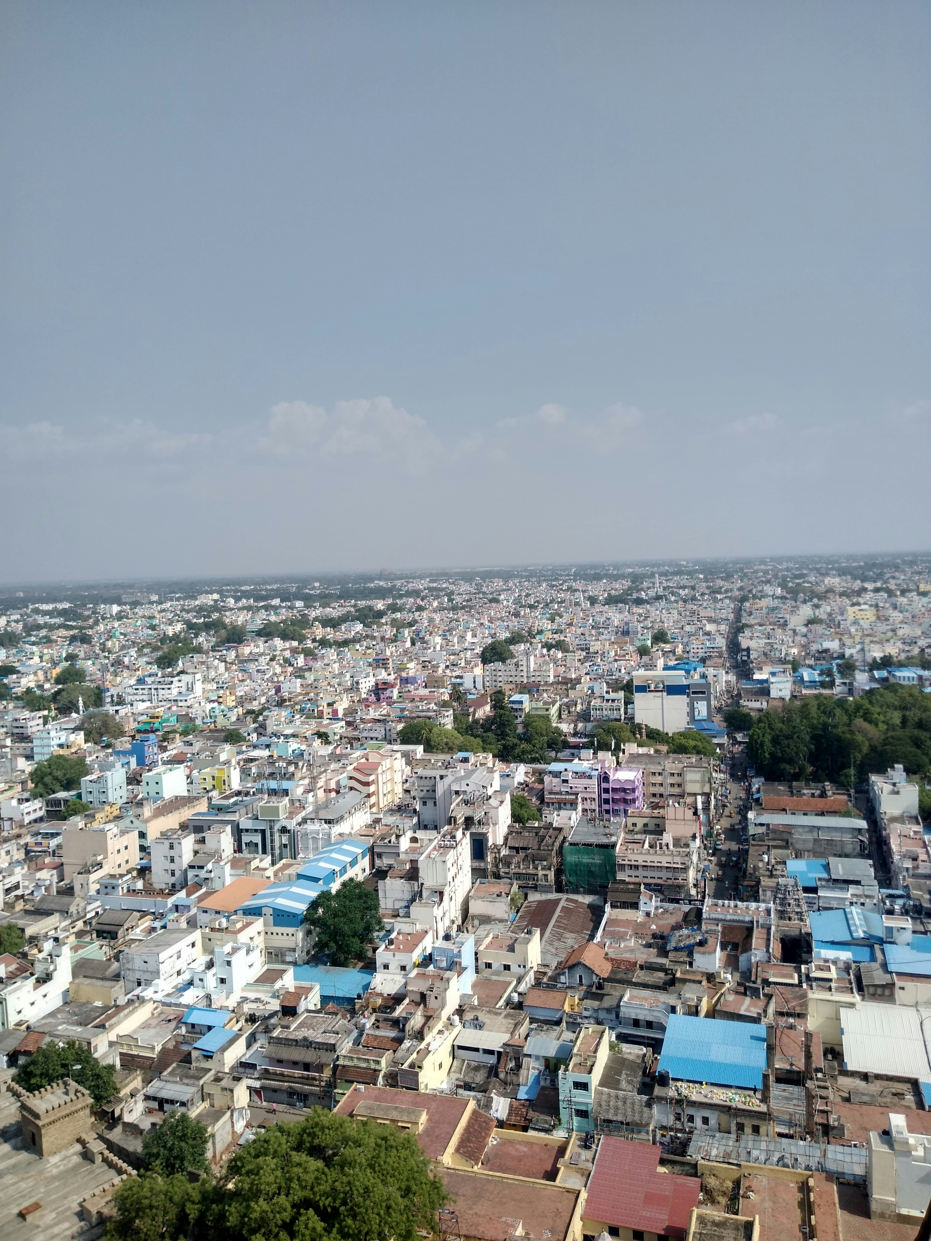 Vast cityscape showcasing a patchwork of colorful rooftops and buildings under a clear sky. The scene captures the essence of urban density and architectural diversity.