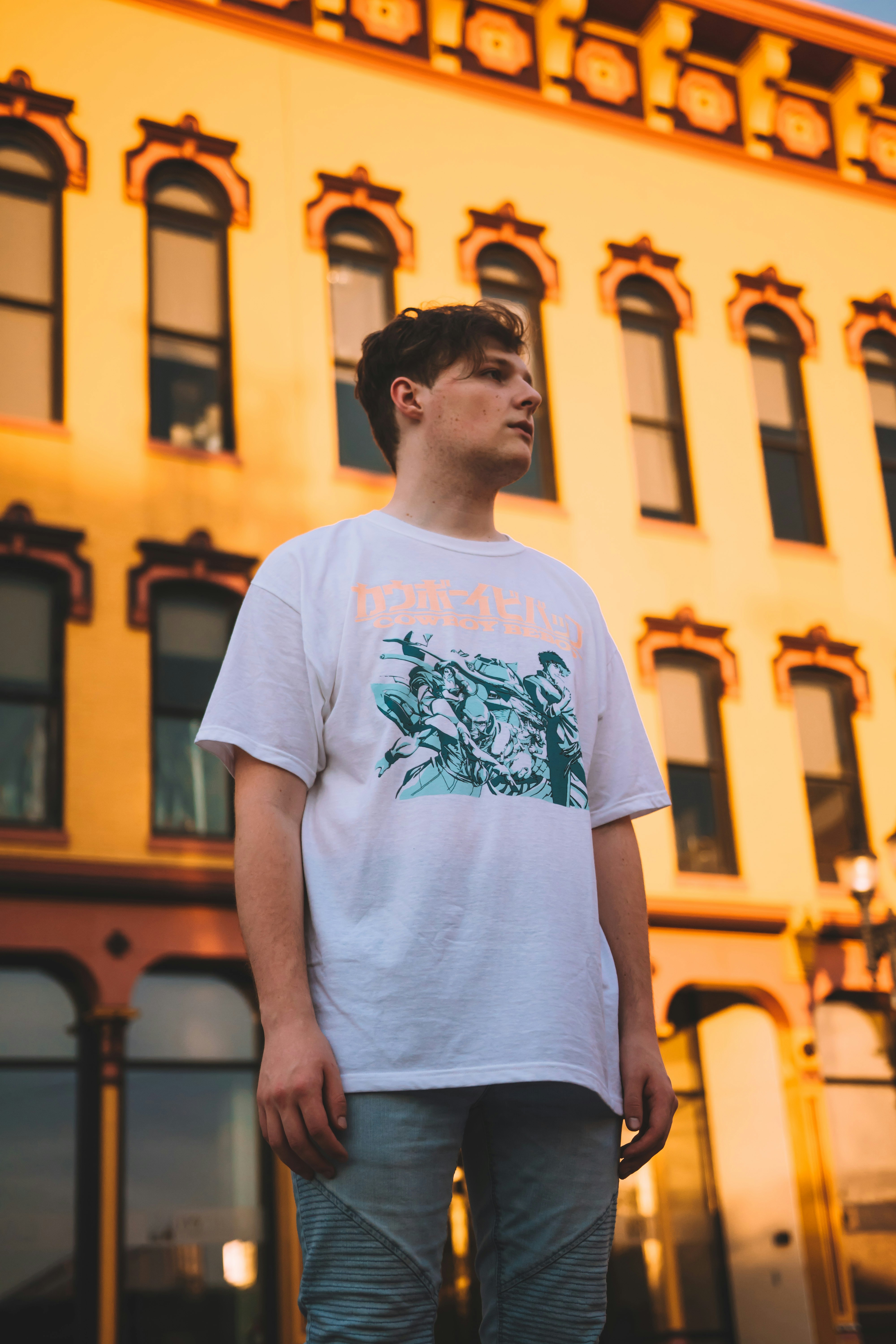 man in white and green crew-neck t-shirt standing near building