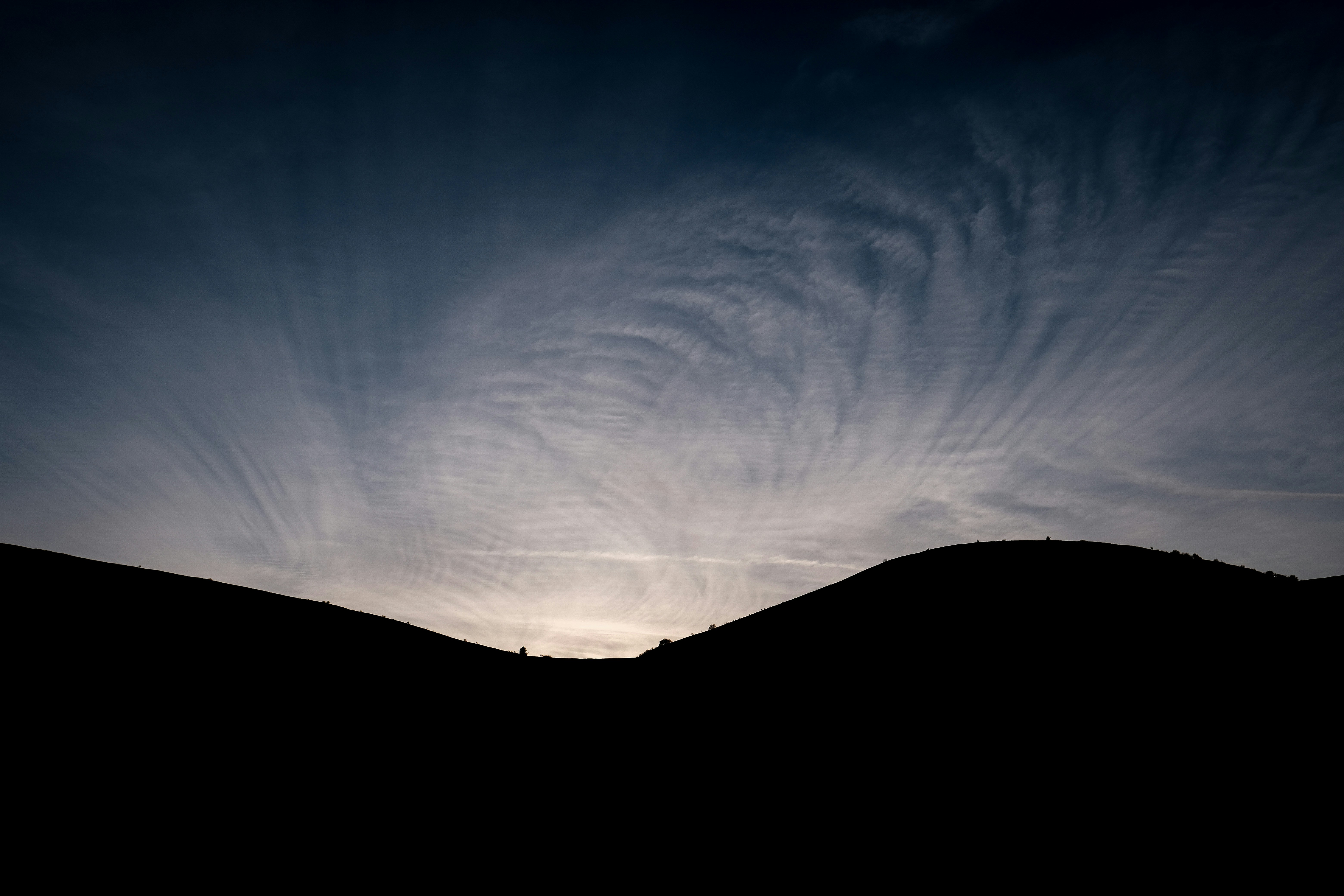 Cold weather skies as the setting sun silhouettes mountains viewed from Llanthony Abbey in Wales.