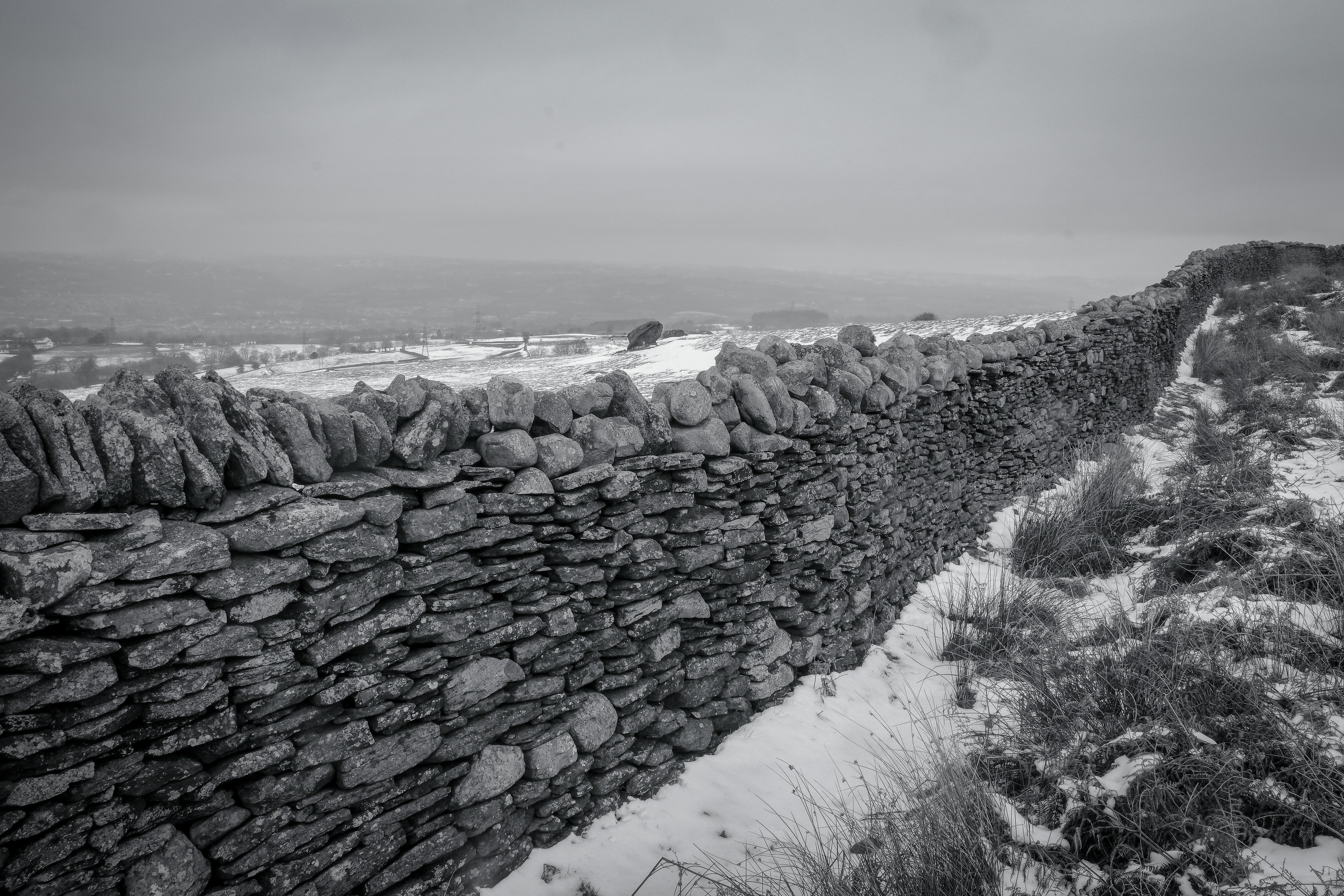 Dry stone wall in the snow above Nelson, South Wales. Black and White Landscape.