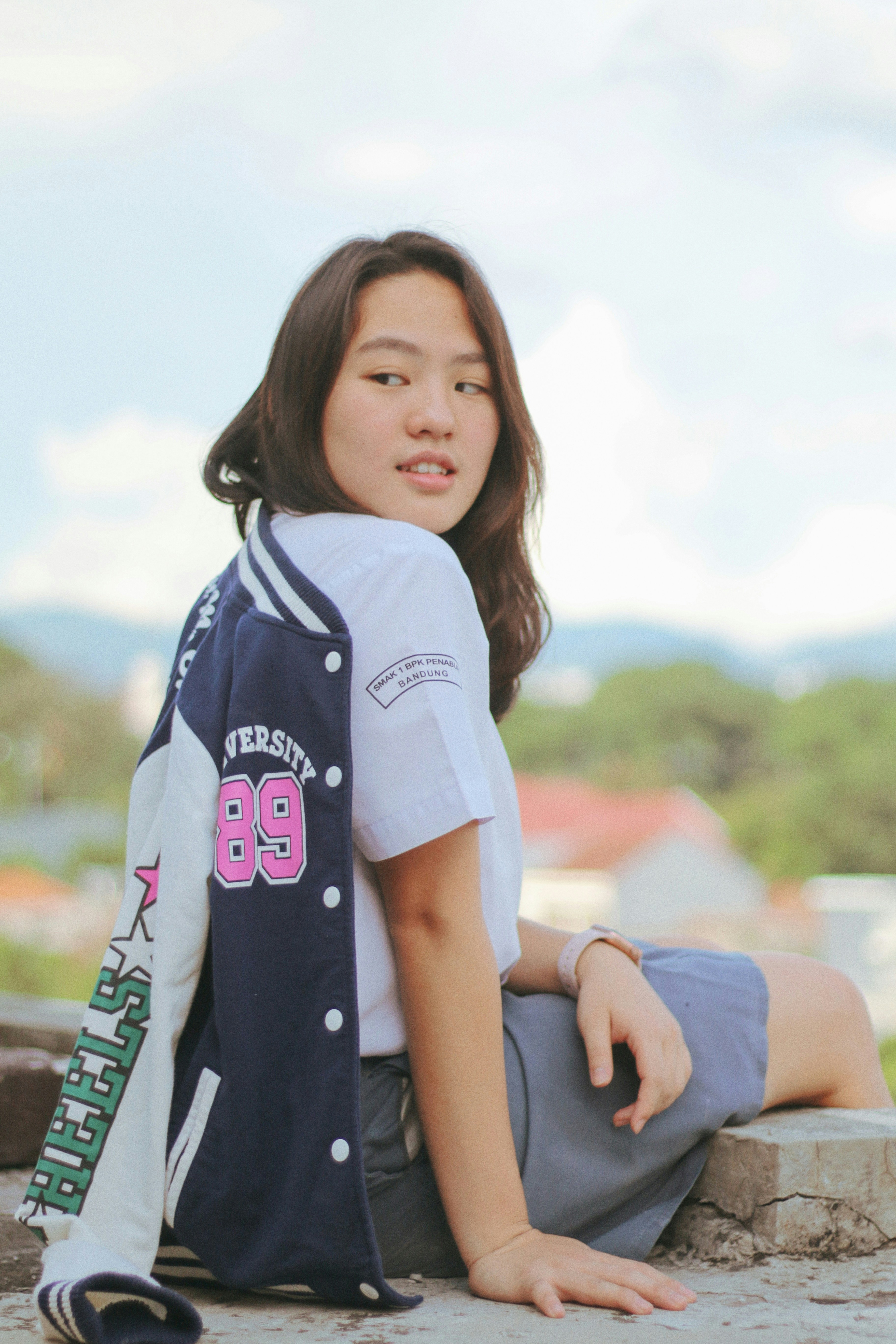 Over-the-Shoulder Look in a Varsity Jacket on a Sunlit Rooftop
