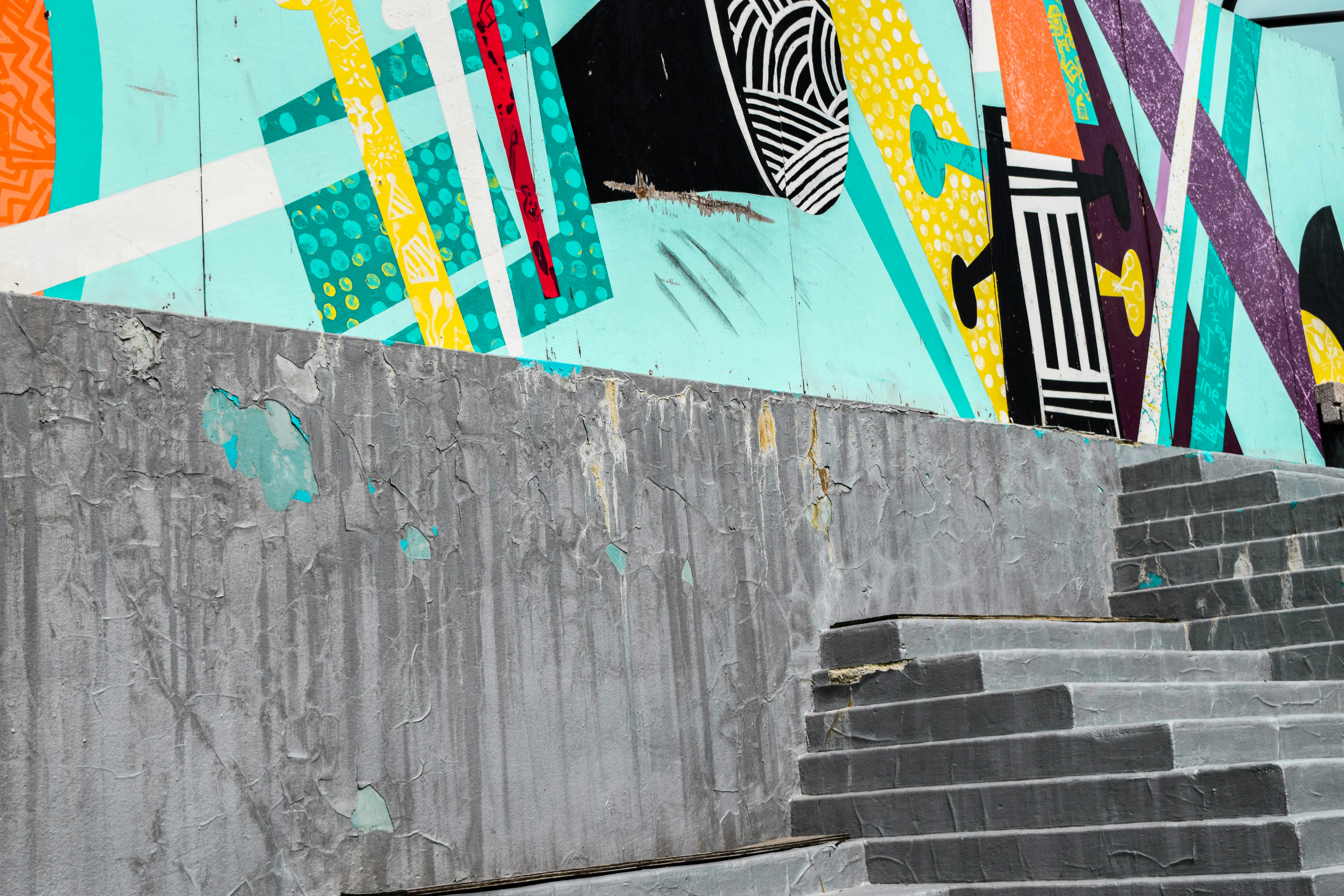 Vibrant mural on a concrete wall juxtaposed with weathered steps, showcasing urban artistry and decay.