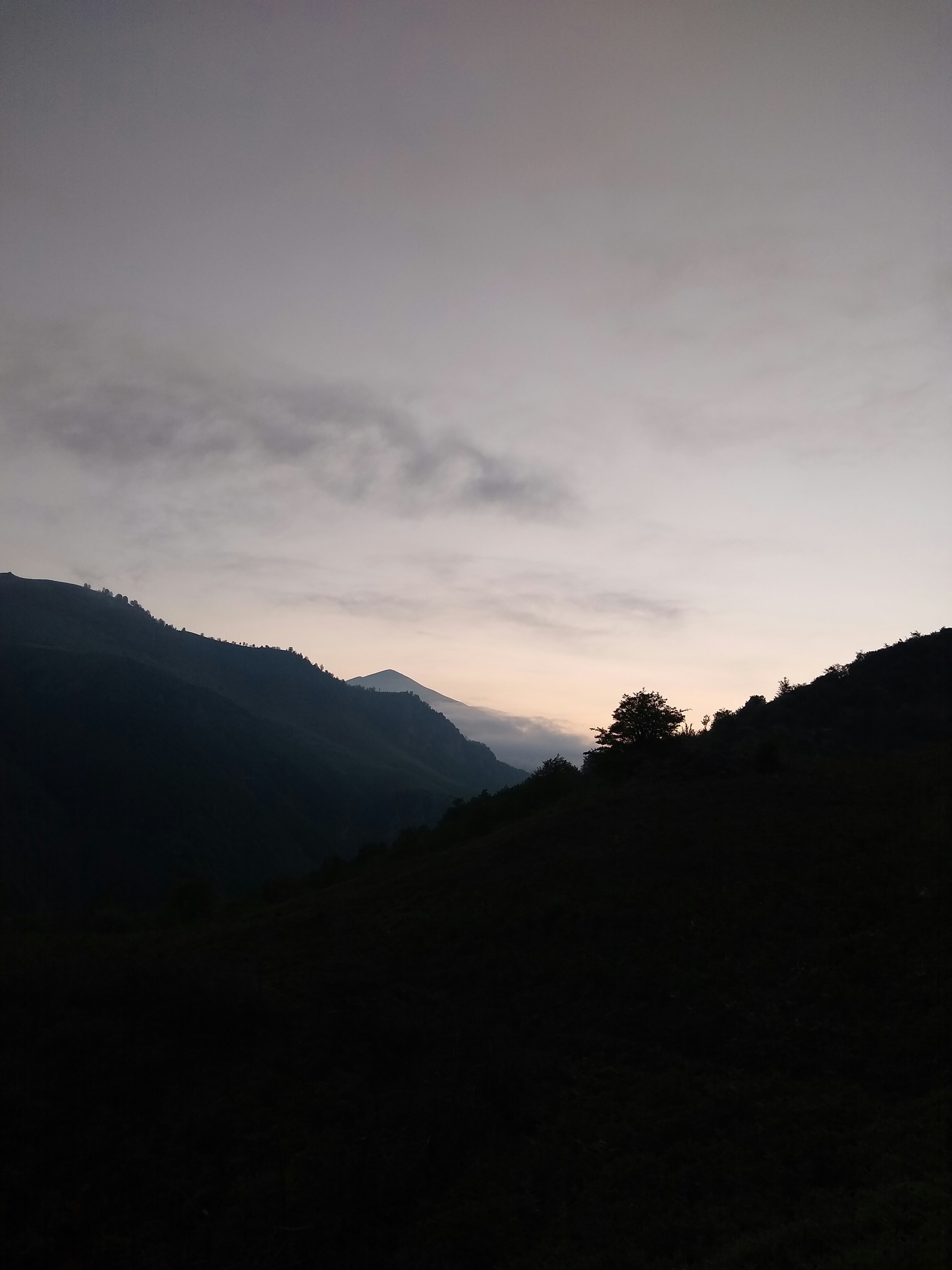 Silhouetted hills against a fading twilight sky with subtle cloud patterns.