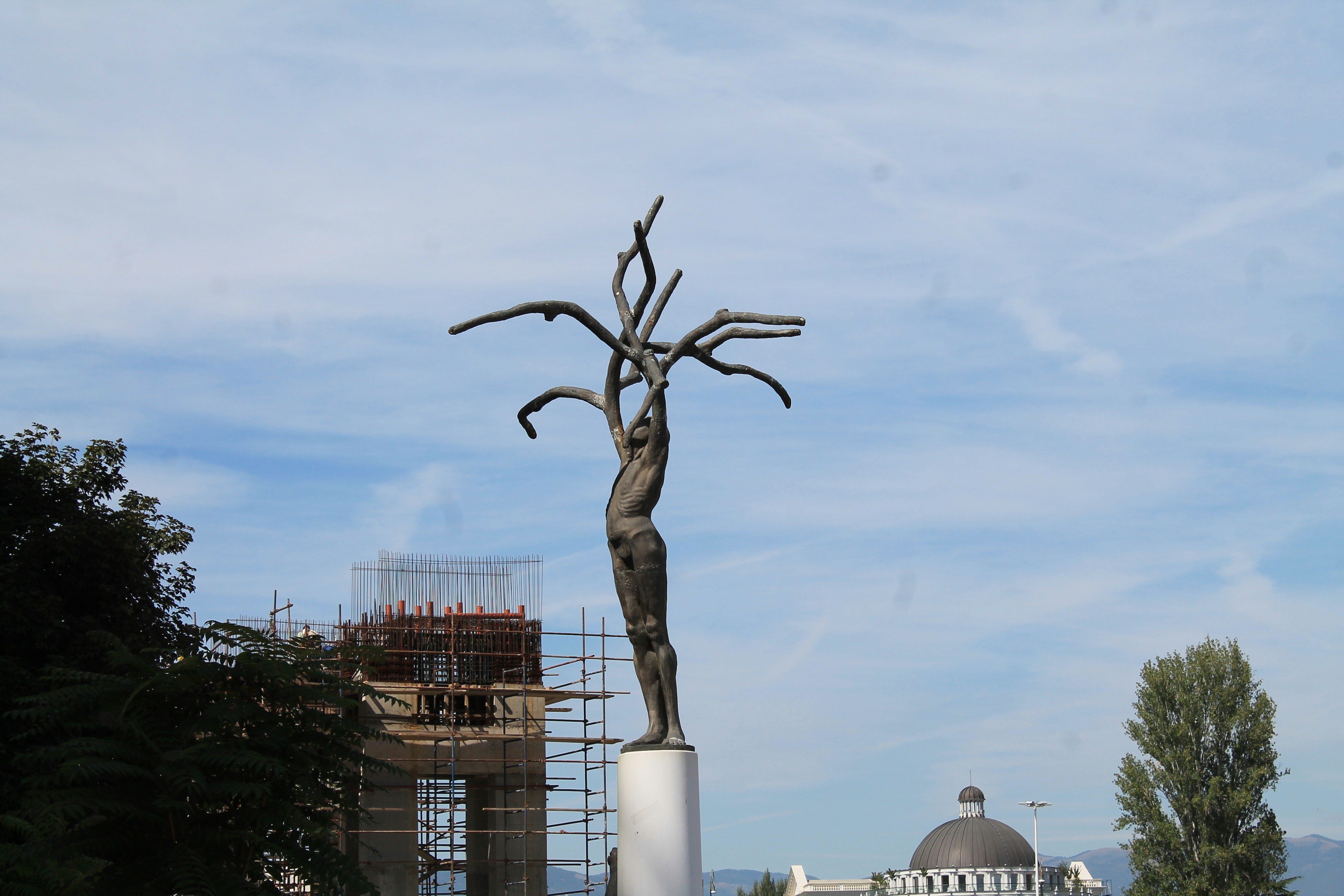 Branching Sentinel: A Skeletal Steel Figure Rising Over the City Square
