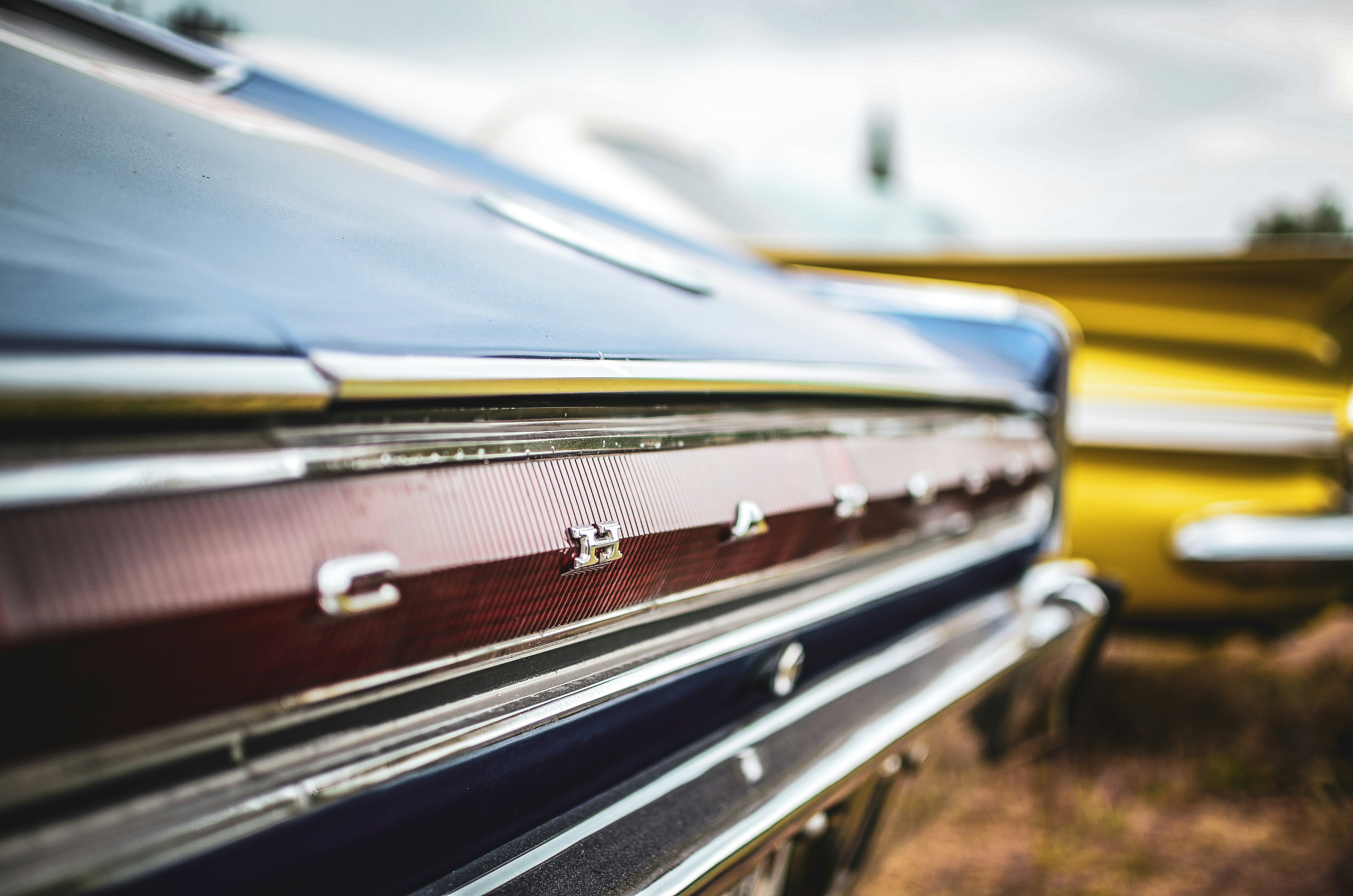 Chrome and Color: Close-Up of Vintage Car Emblems in a Field