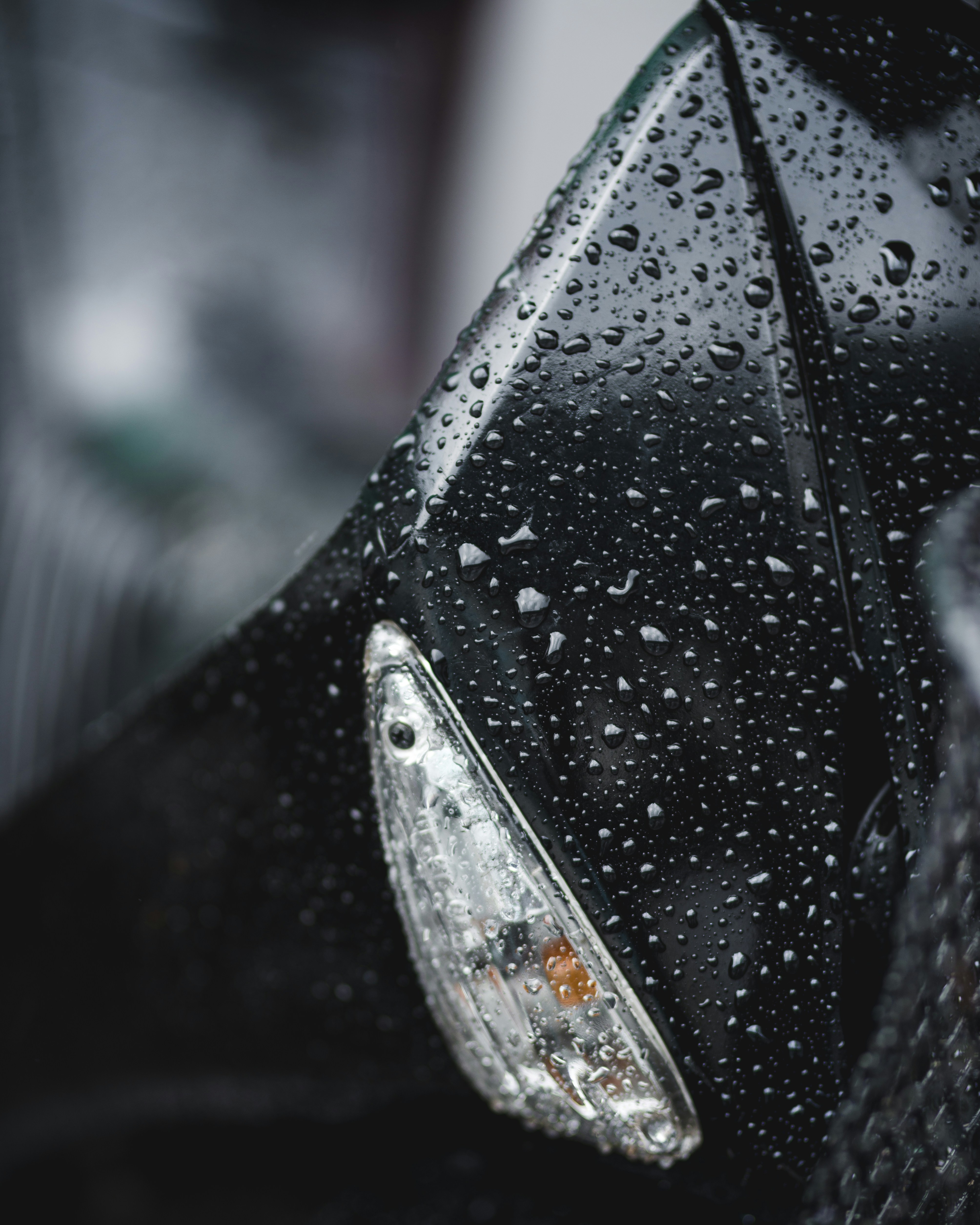 Rain-Kissed Contours: Close-Up of a Black Car Front with Droplet Detail