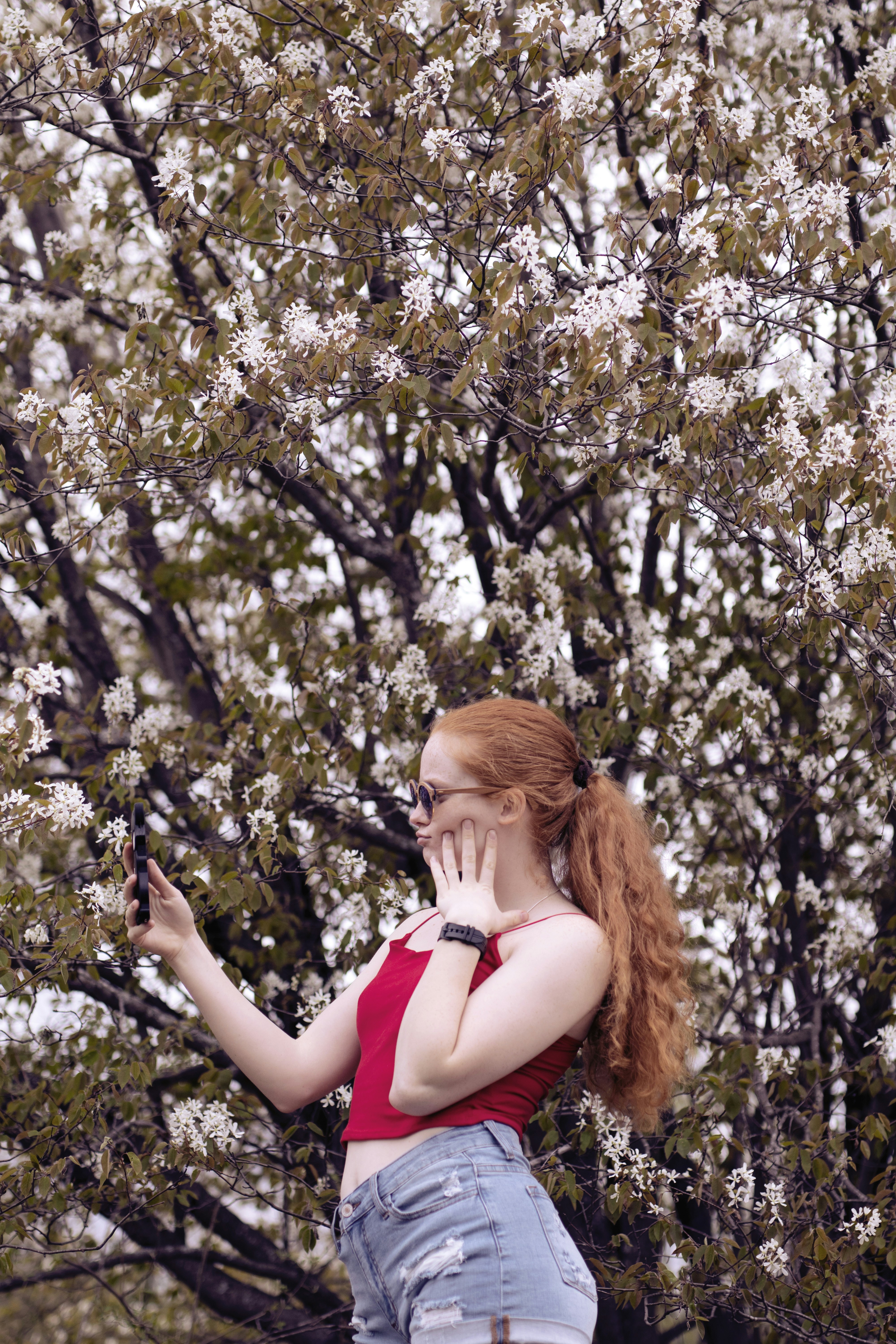 Selfie in Bloom: Red-Haired Portrait Among White Blossoms