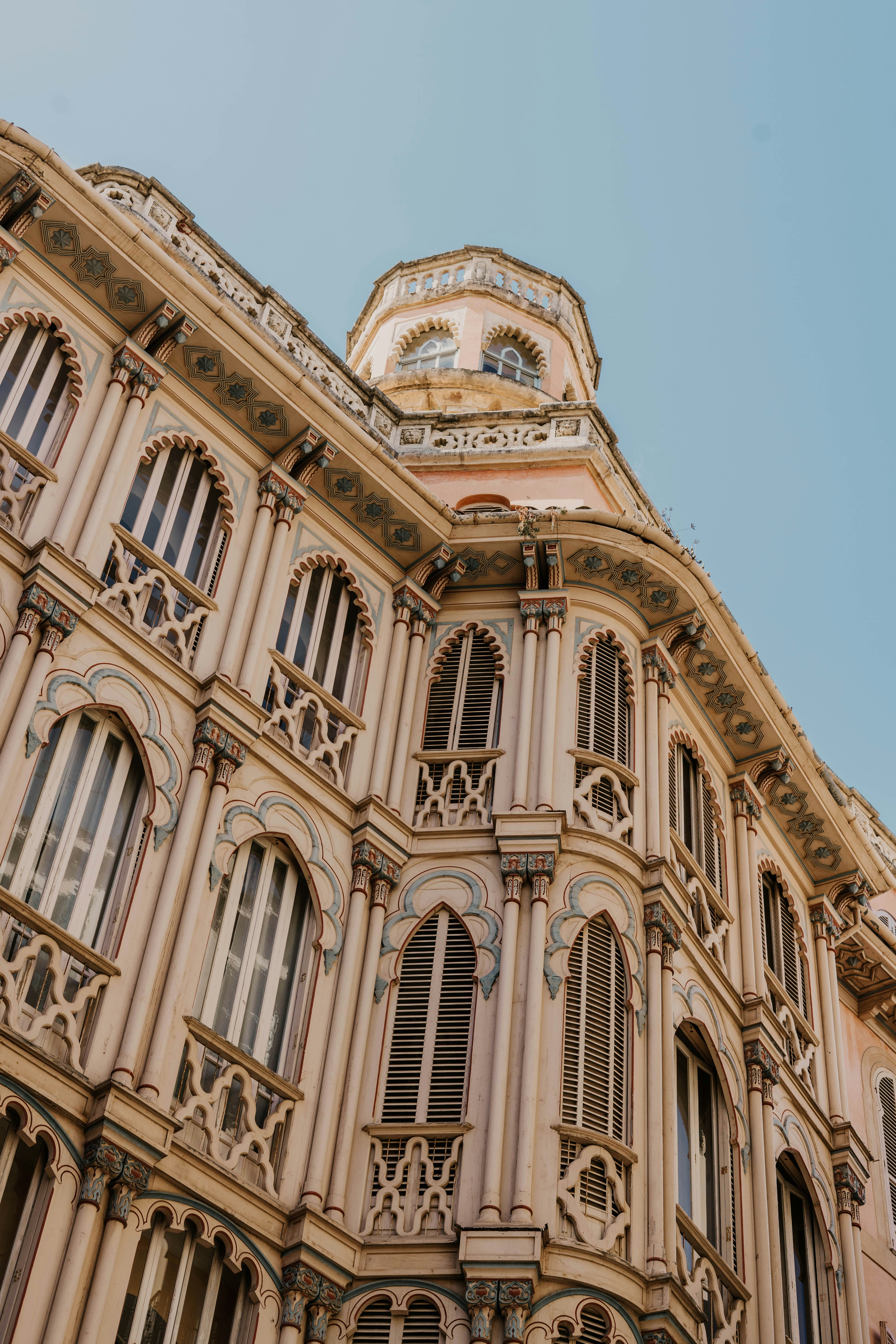 Arched Reverie: A Low-Angle Portrait of an Ornate Peach Facade Against a Pristine Sky