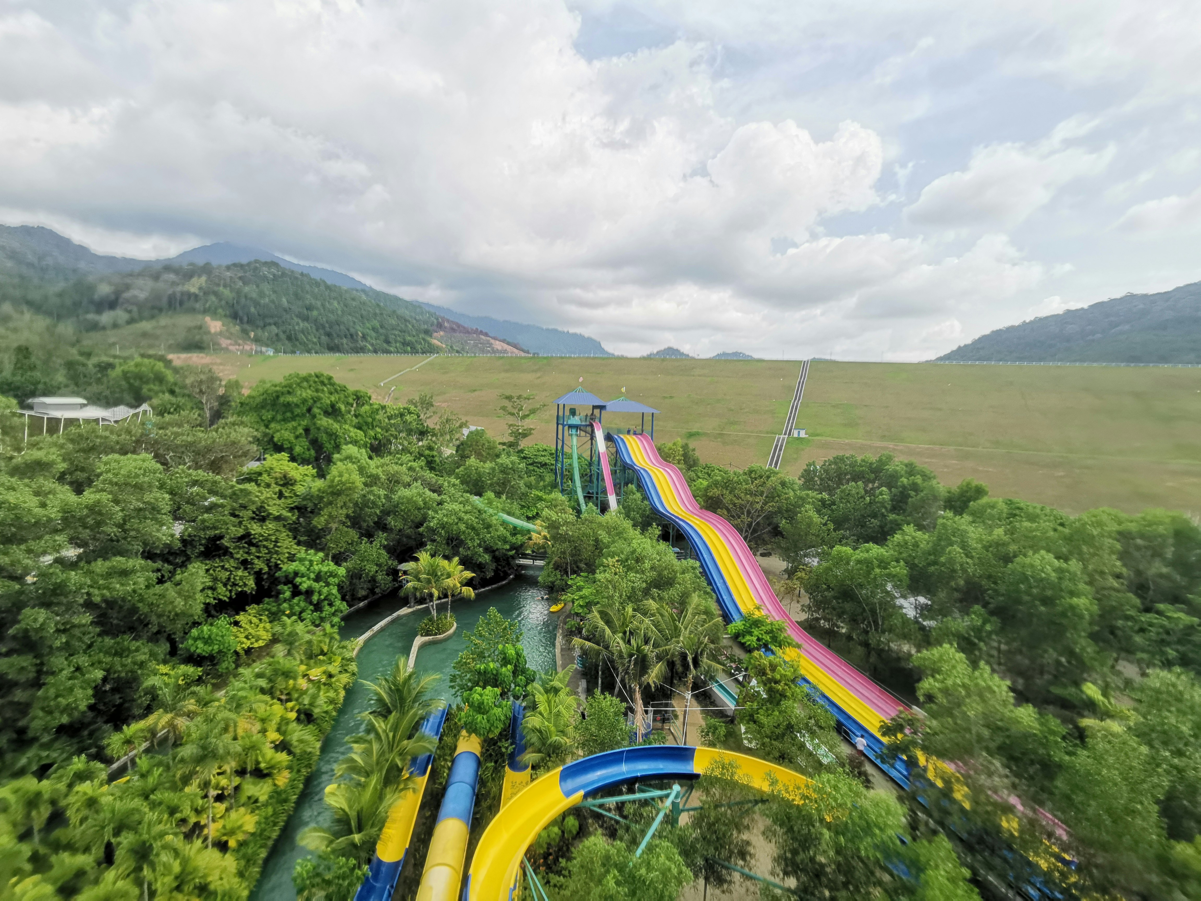 Colorful water slides winding through lush greenery under a cloudy sky.