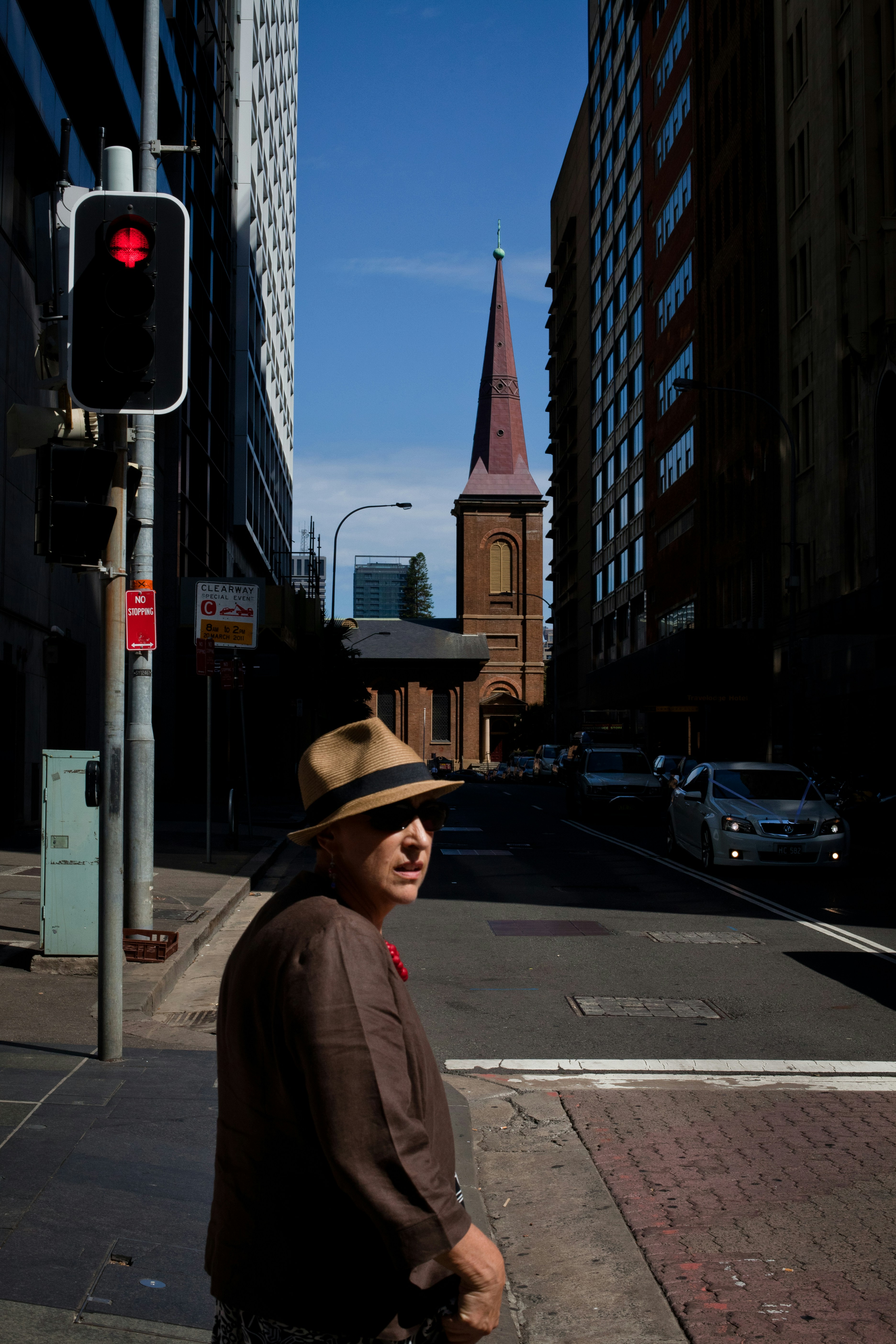Man standing on concrete pathway near traffic light showing red stop ...
