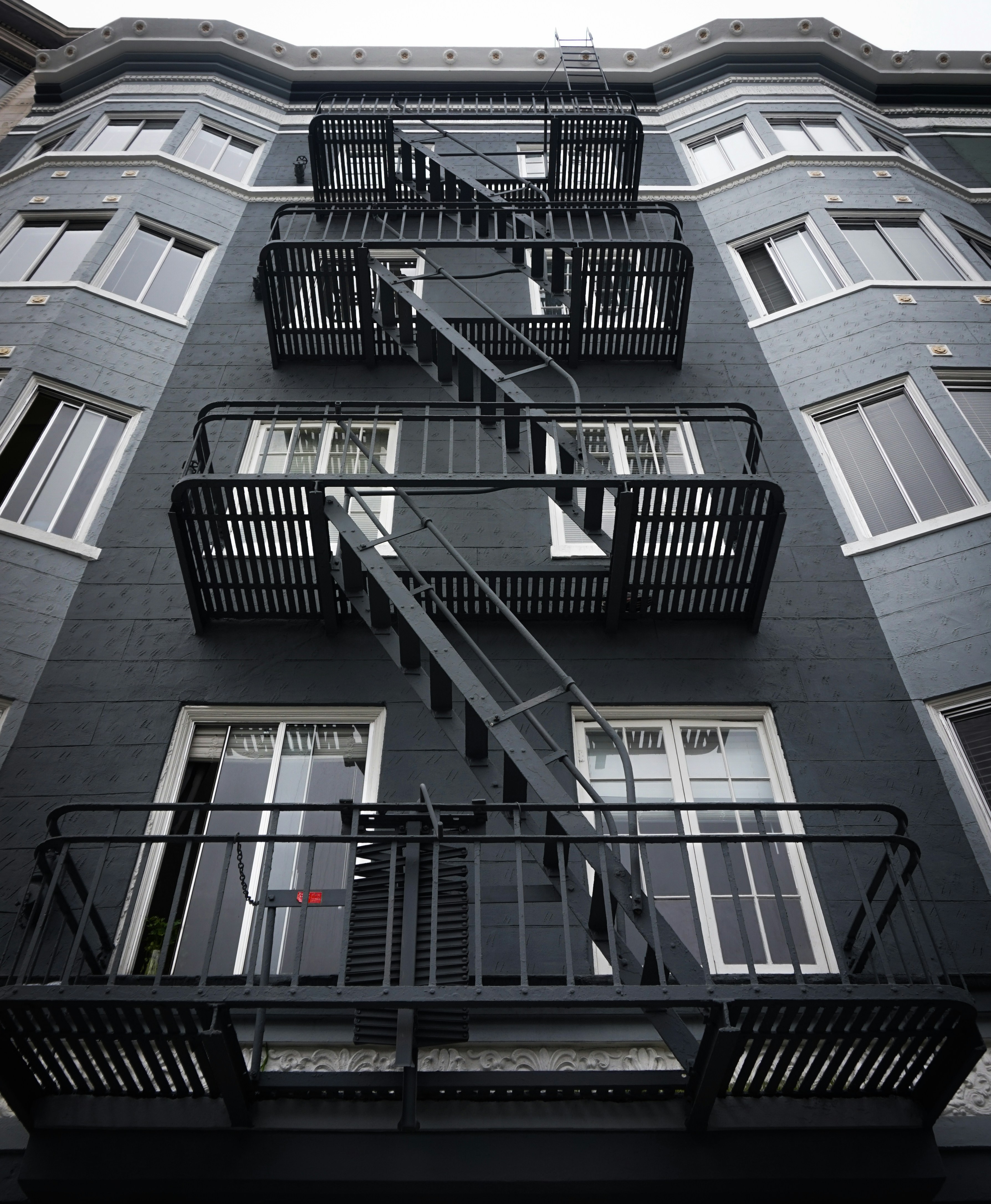 A symmetrical view of a building's fire escape, showcasing its intricate metalwork against a dark facade. The design emphasizes urban architecture and safety features.