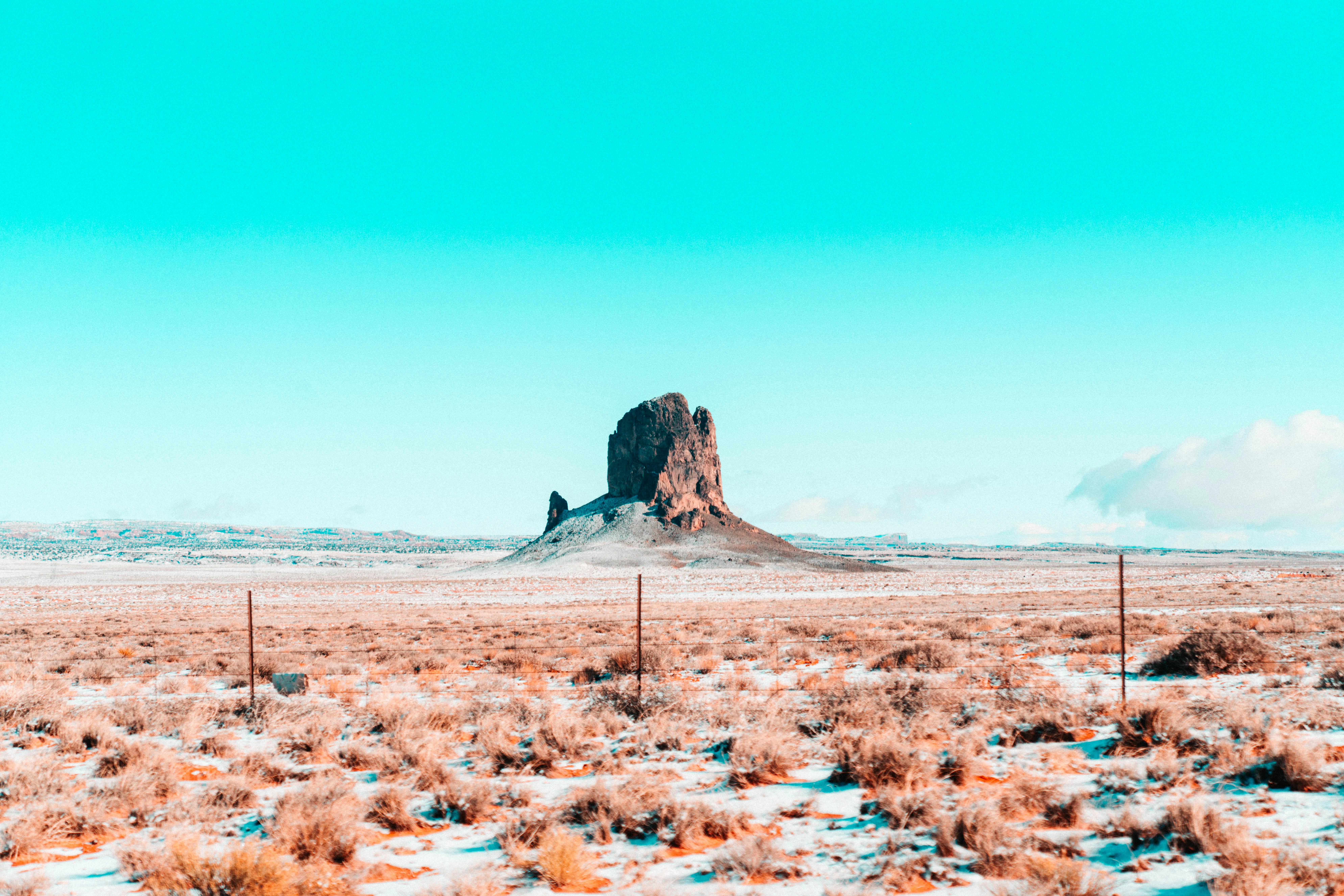 Lone Monolith Amid a Snow-Dusted Desert Beneath an Electric Cyan Sky