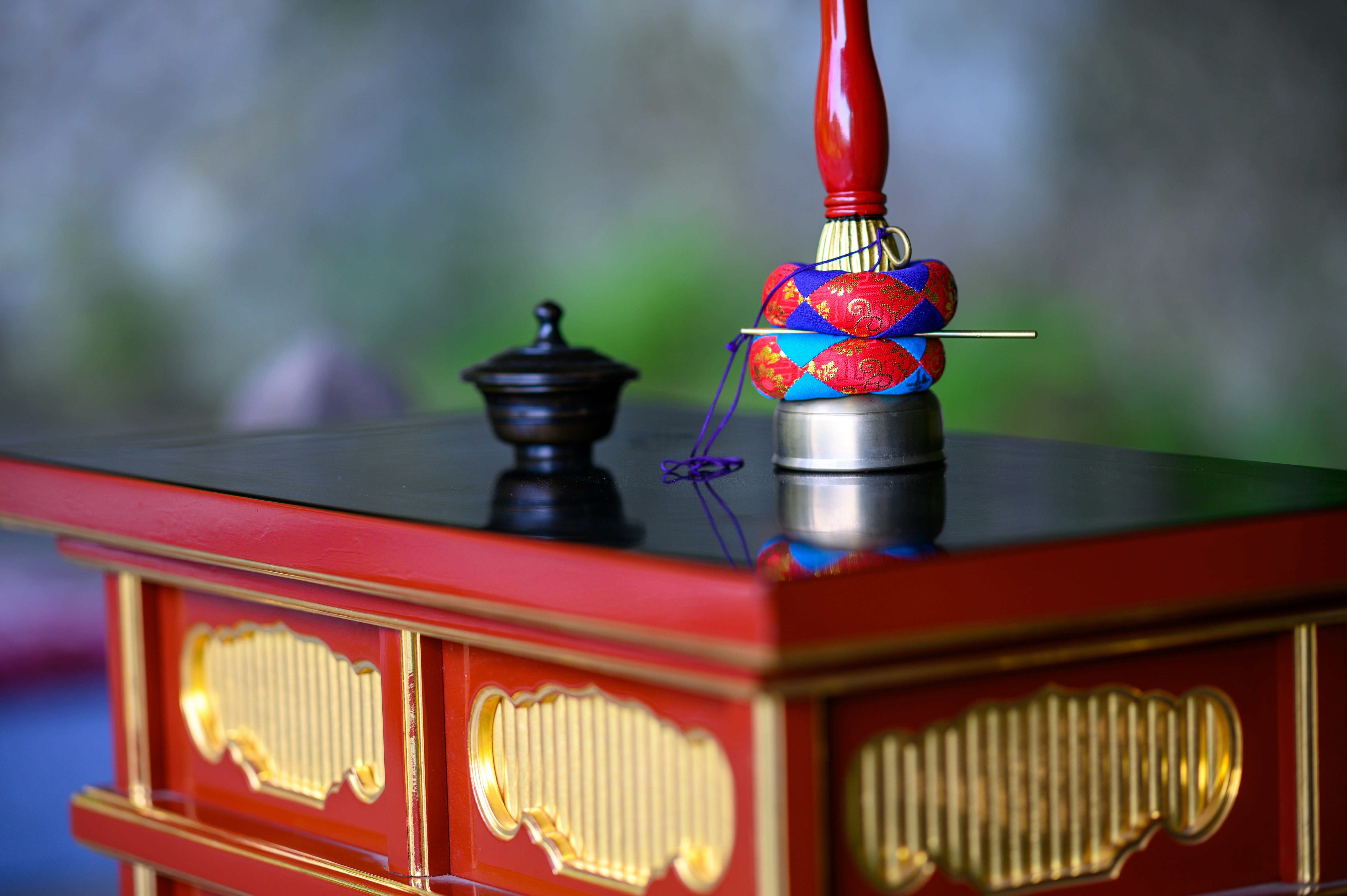 Ceremonial Stopper: A Red Lacquered Altar With a Painted Knot and Metallic Finial